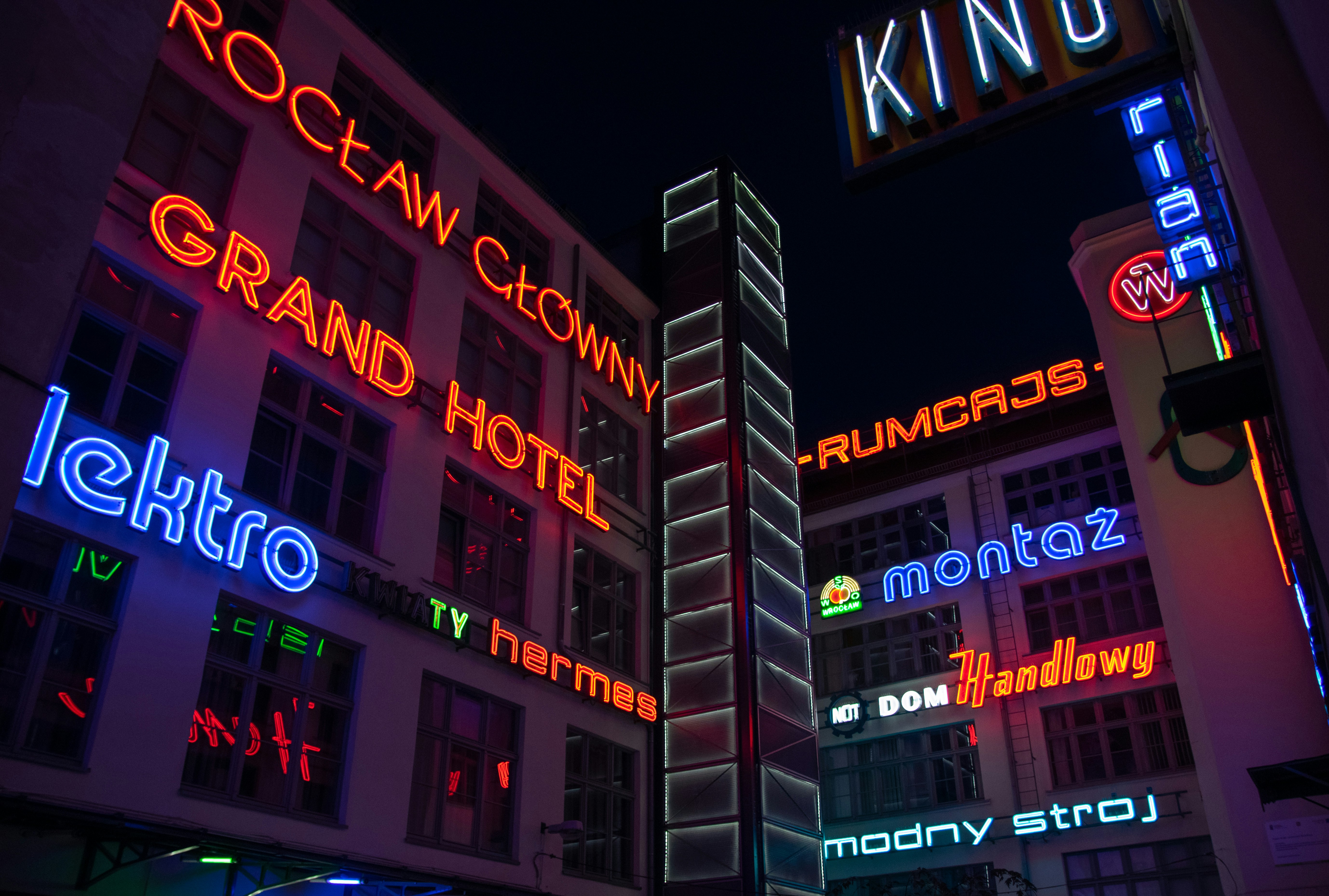 A building with neon signs lit up at night photo – Free Poland Image on ...