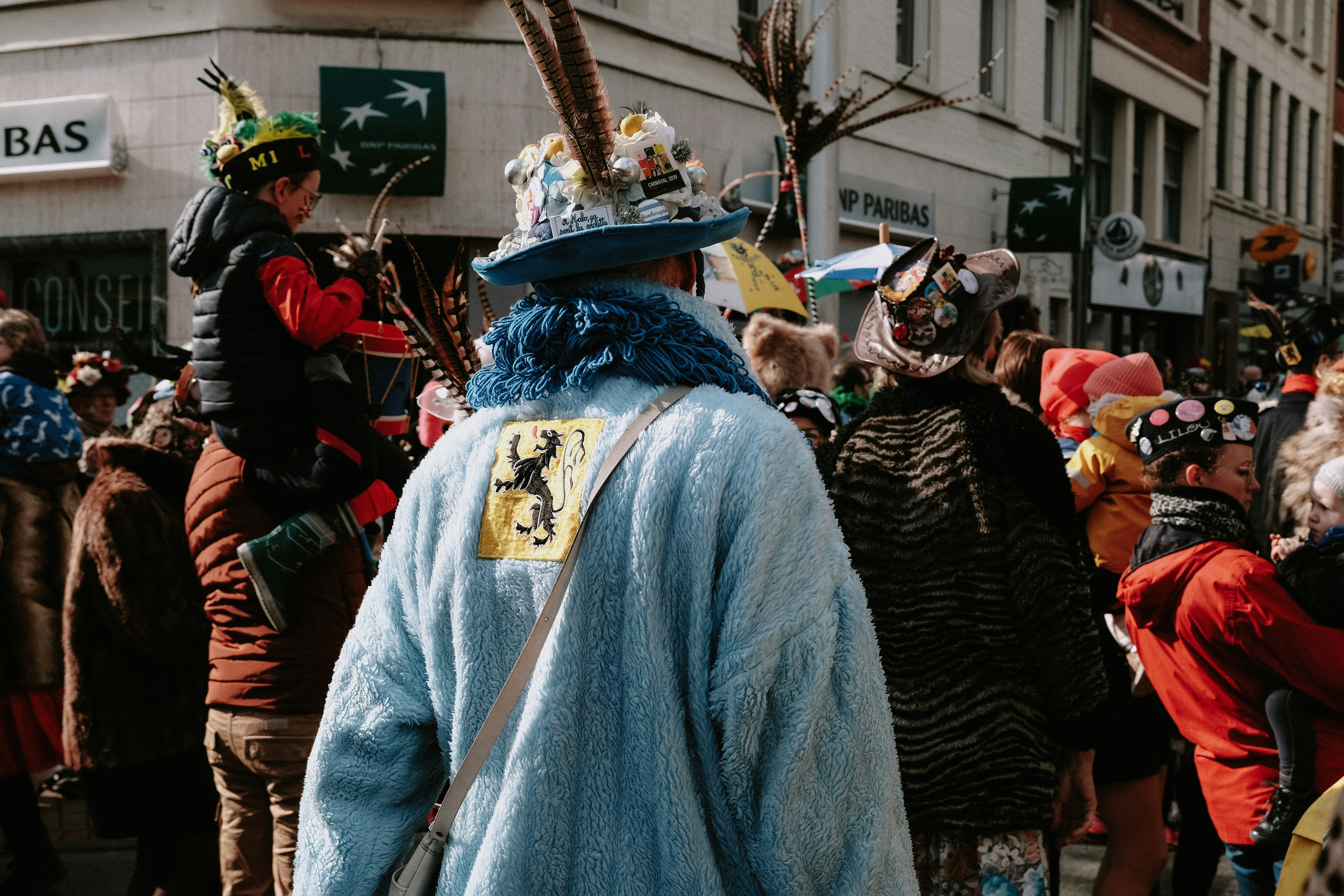 A group of people walking down a street next to tall buildings photo ...