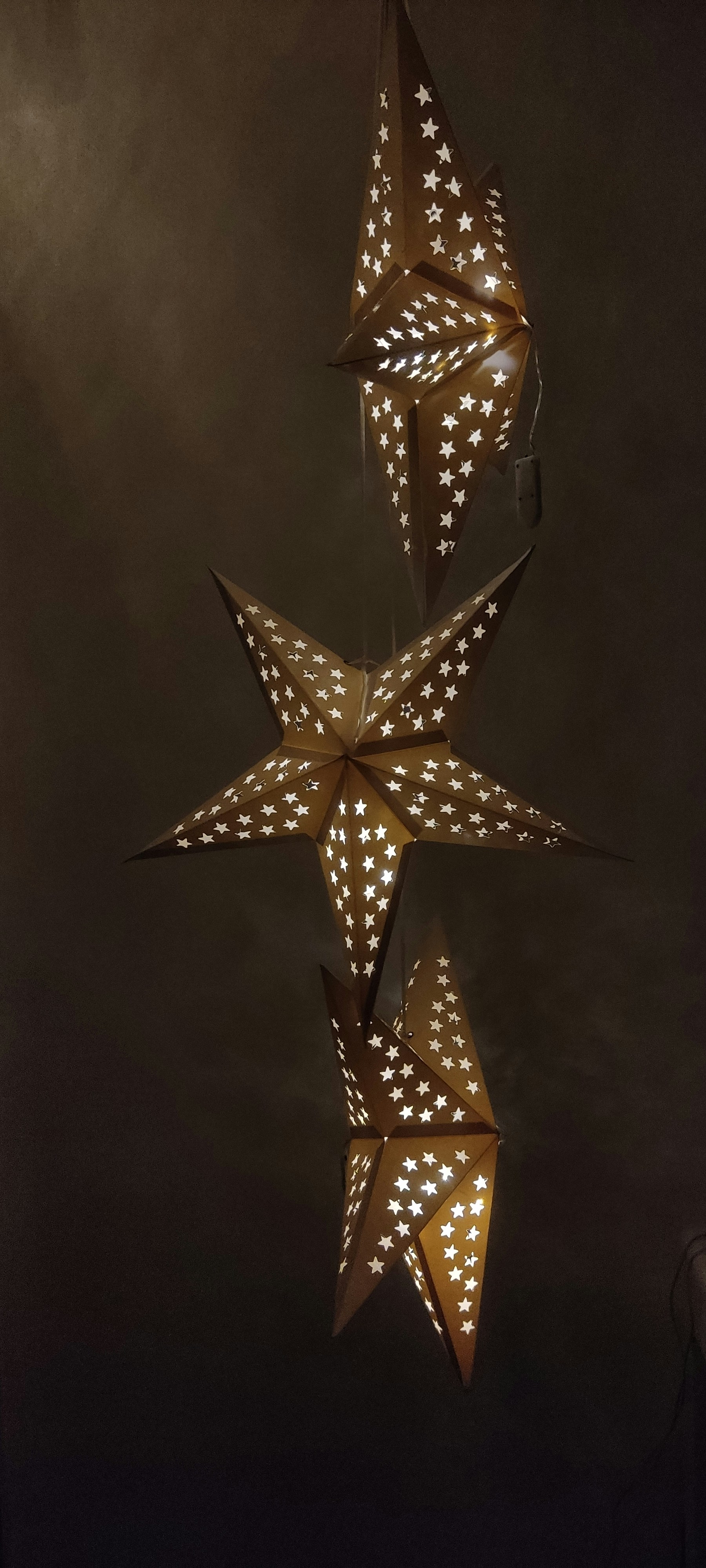 Three intricately designed star-shaped lanterns glowing softly against a dark background.