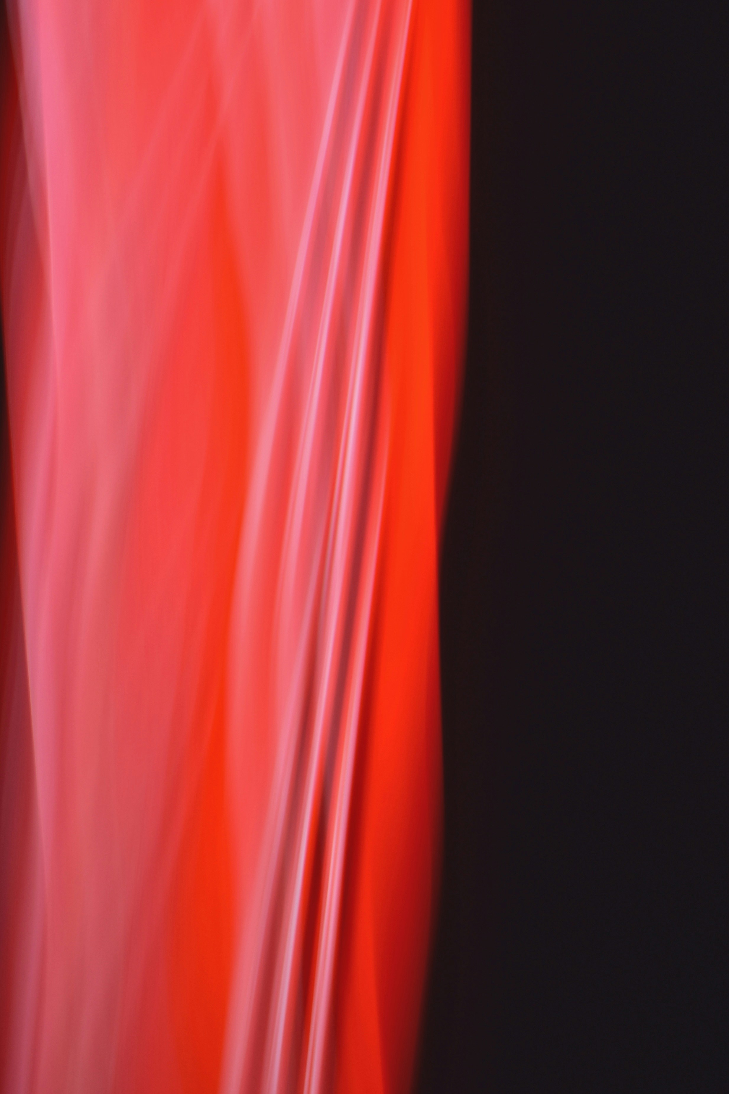 Flowing red light creates a dynamic, abstract pattern against a dark backdrop, evoking a sense of movement and energy.