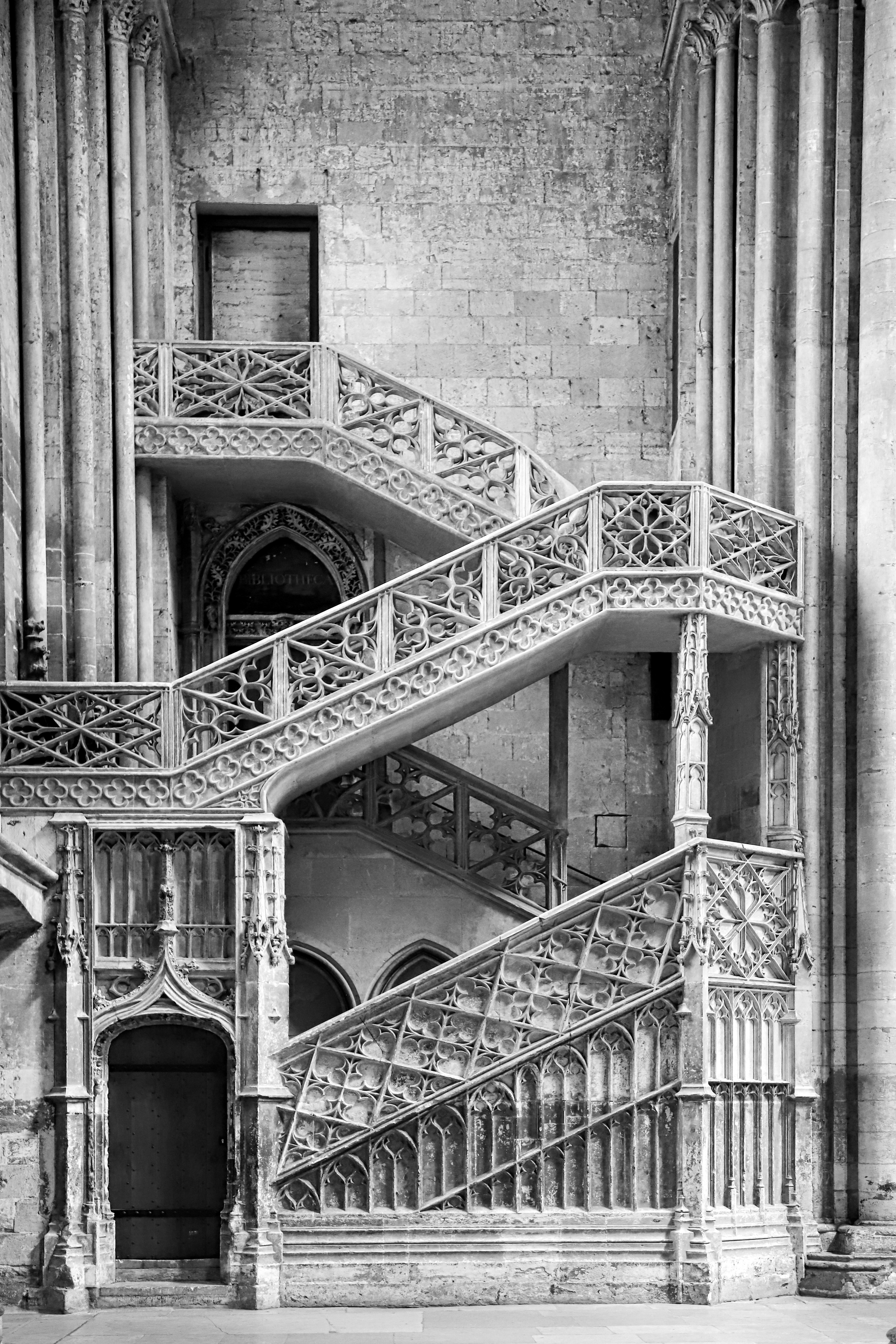Intricately detailed Gothic staircases intertwine against a cathedral's towering stone walls.