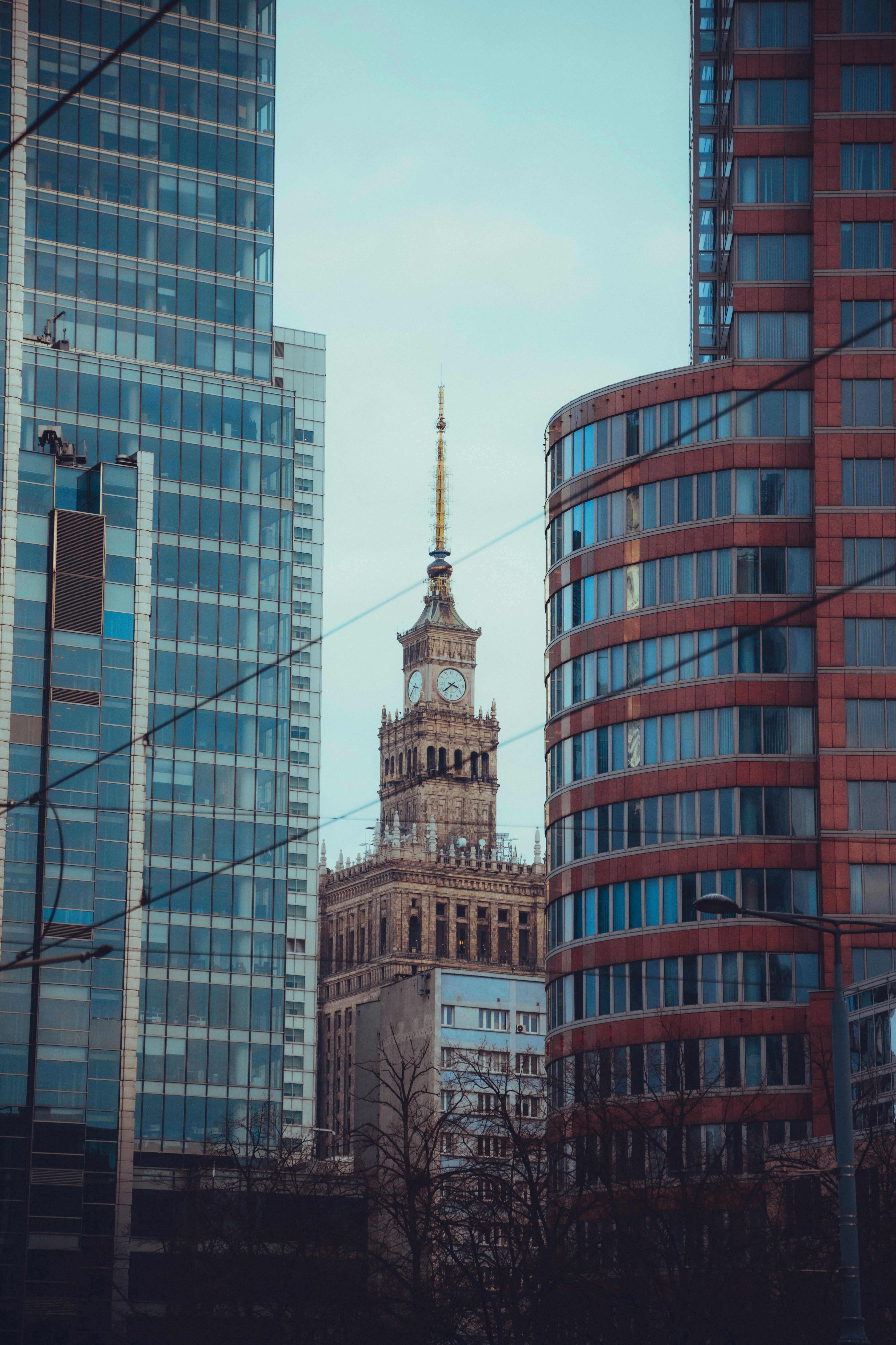 Historic clock tower framed by sleek, contemporary skyscrapers, showcasing the contrast between old and new architecture.