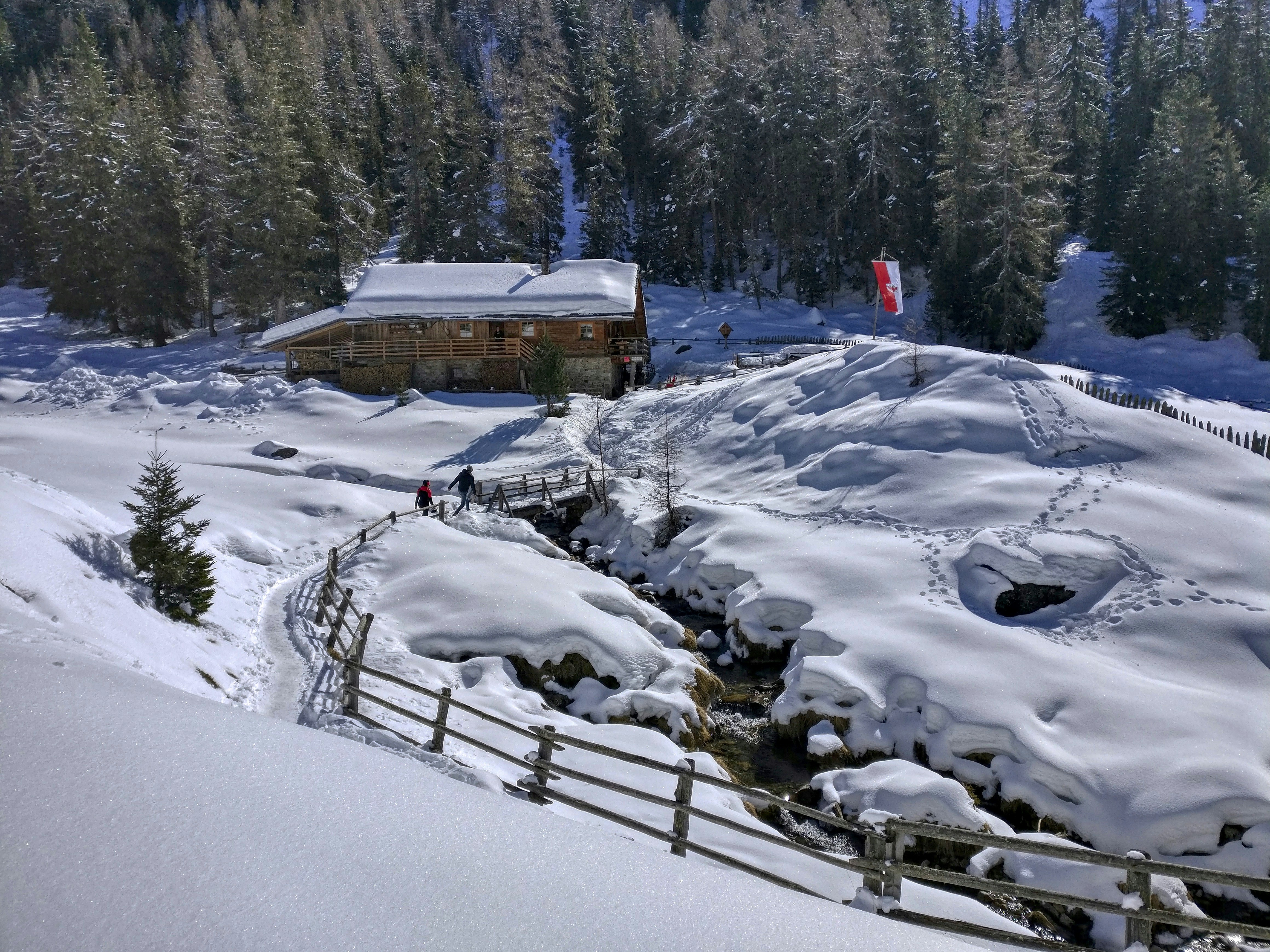 a snow covered hillside with a wooden cabin in the background