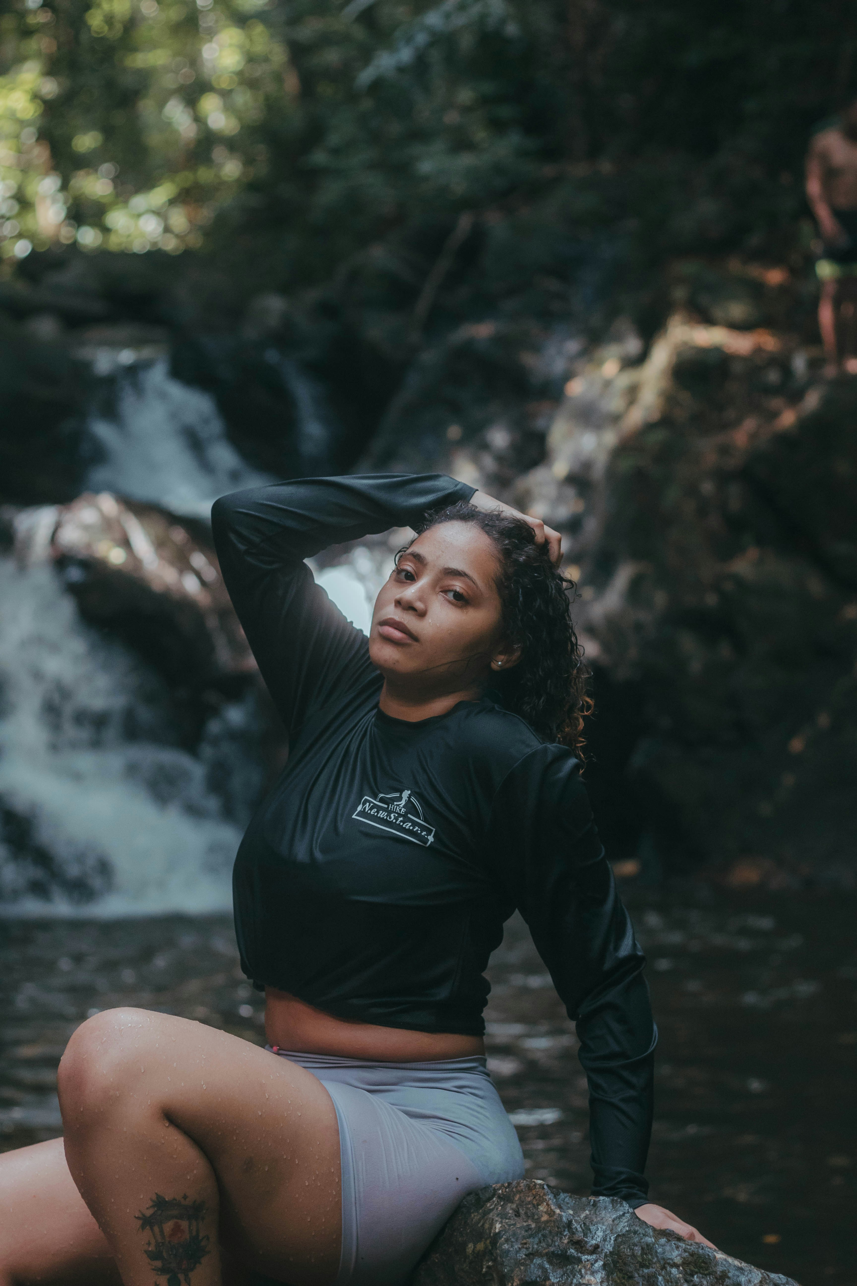 a woman sitting on a rock in front of a waterfall