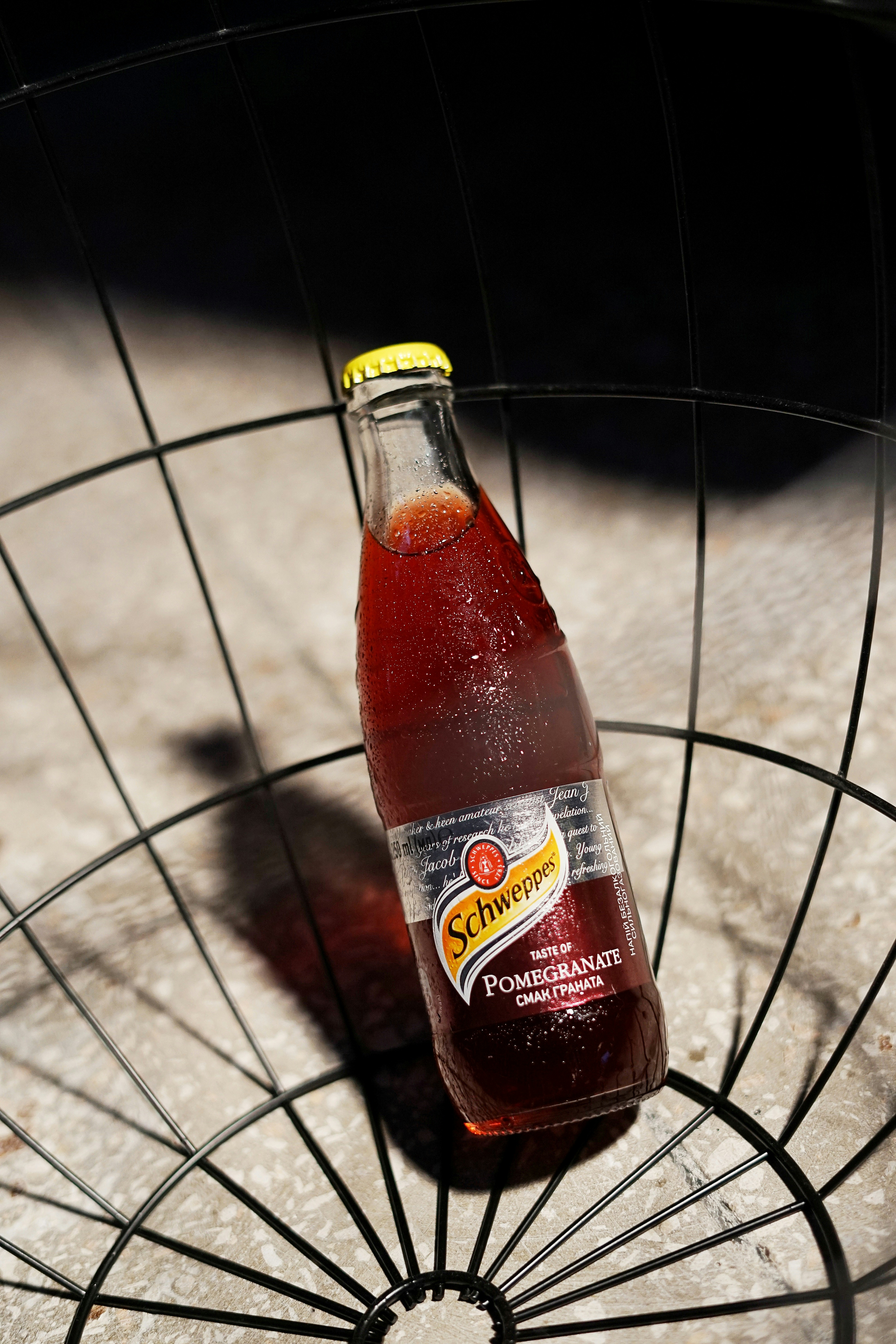 Crimson Schweppes bottle framed by a bicycle wheel's spokes