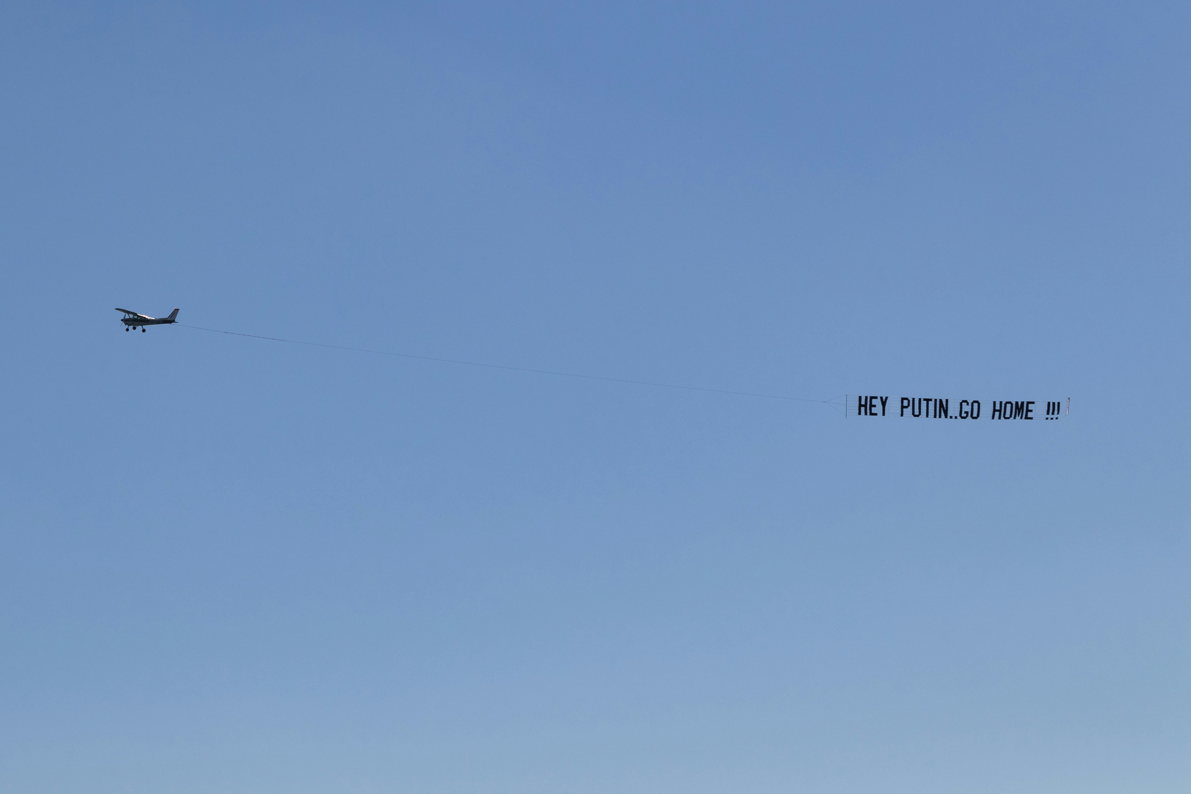 Skyward Messenger: A lone plane tows a banner through a pale-blue expanse