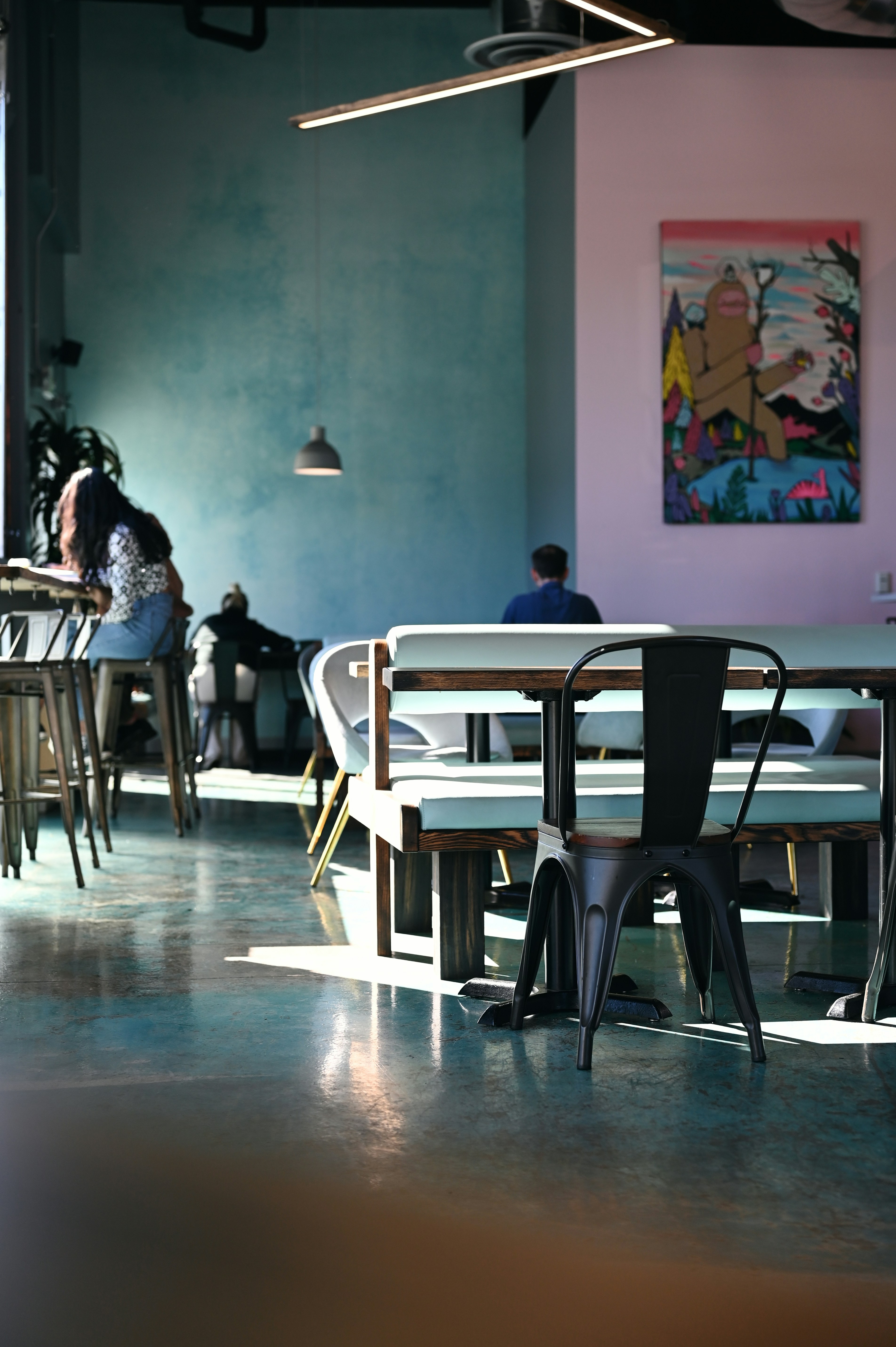 A cozy café interior showcasing modern furniture and vibrant wall art, inviting patrons to relax and socialize.