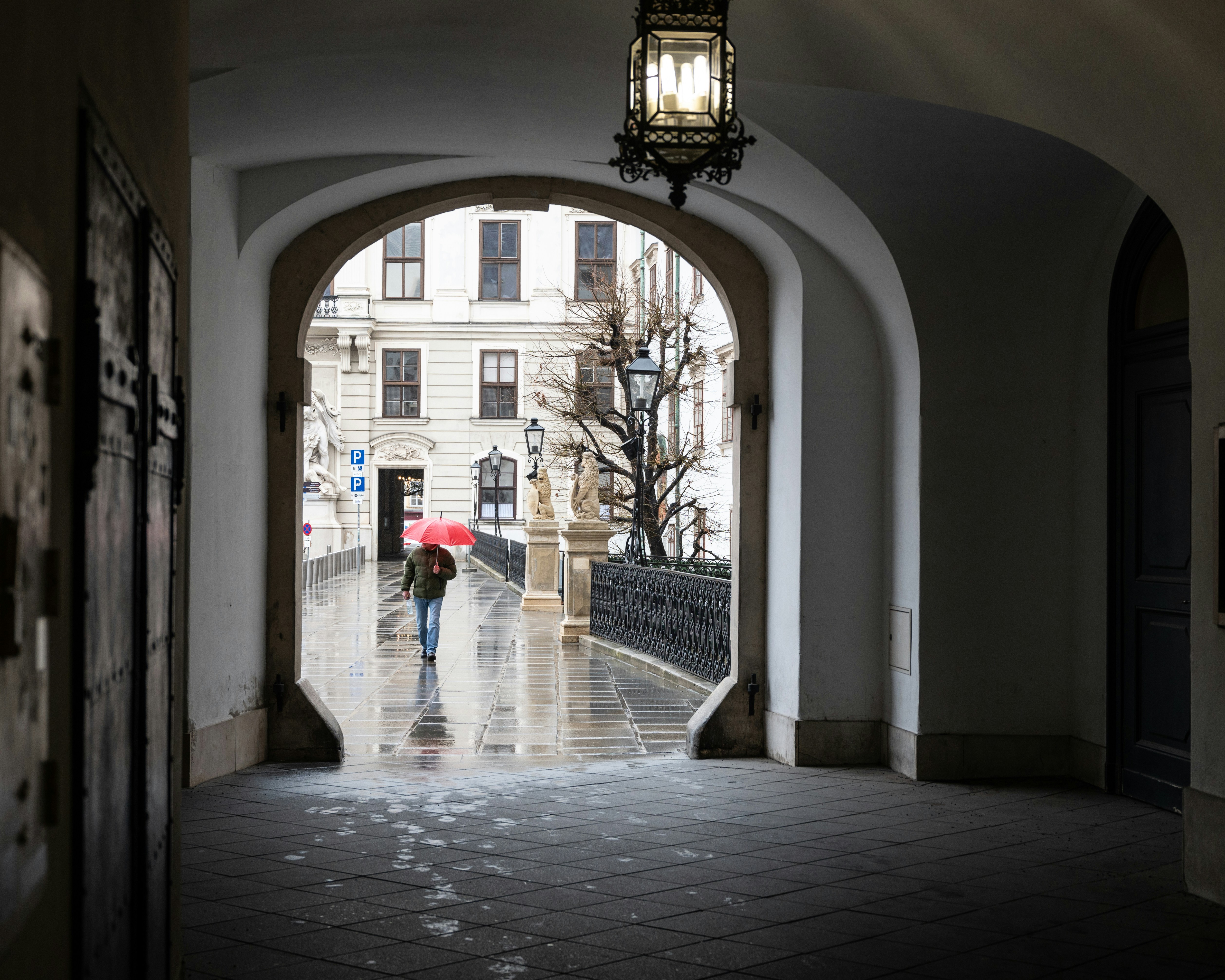 Red Umbrella at the Arch: Rain-Kissed Passage to the Street
