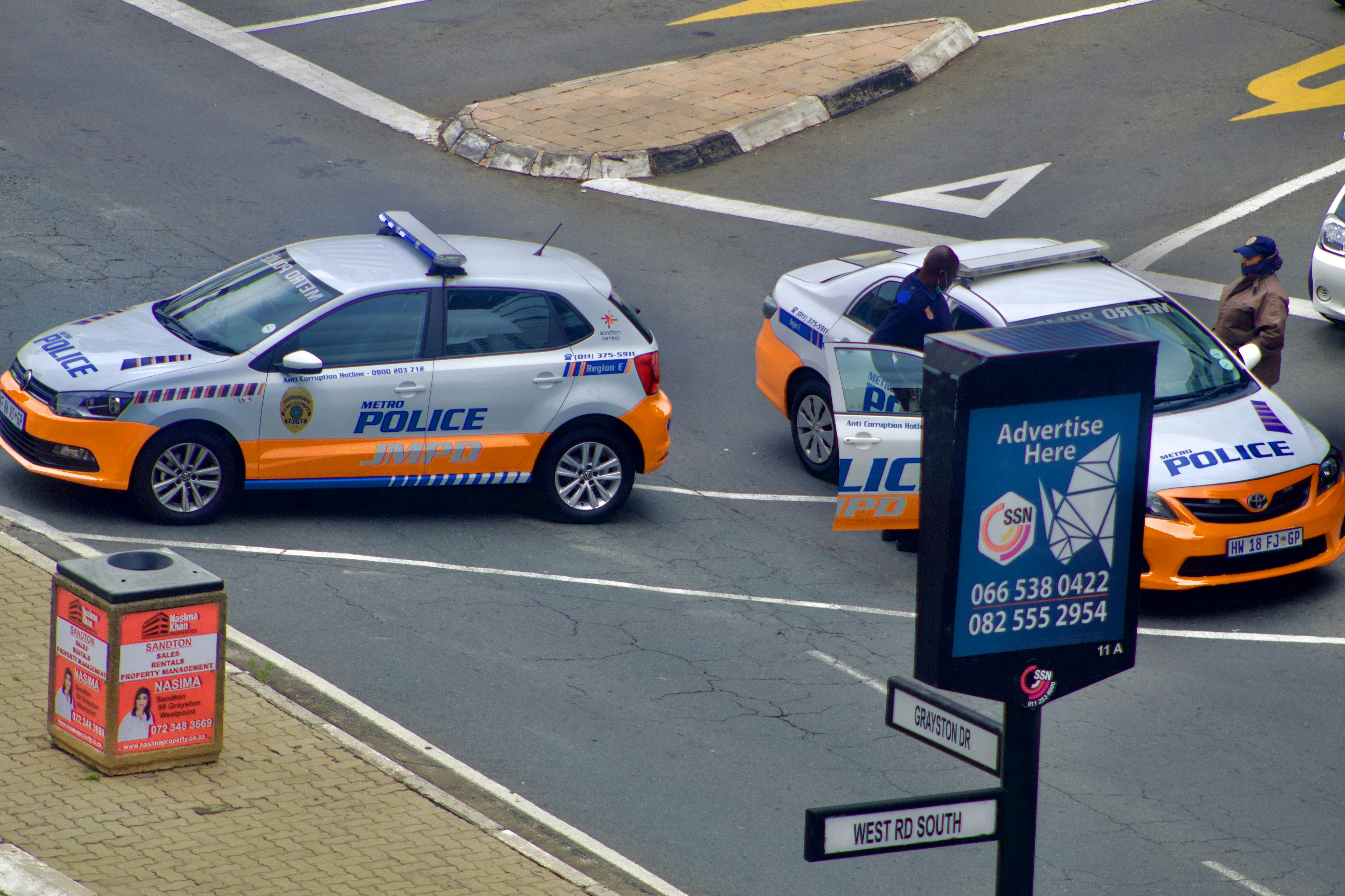 A couple of police cars driving down a street photo – Free Sandton ...