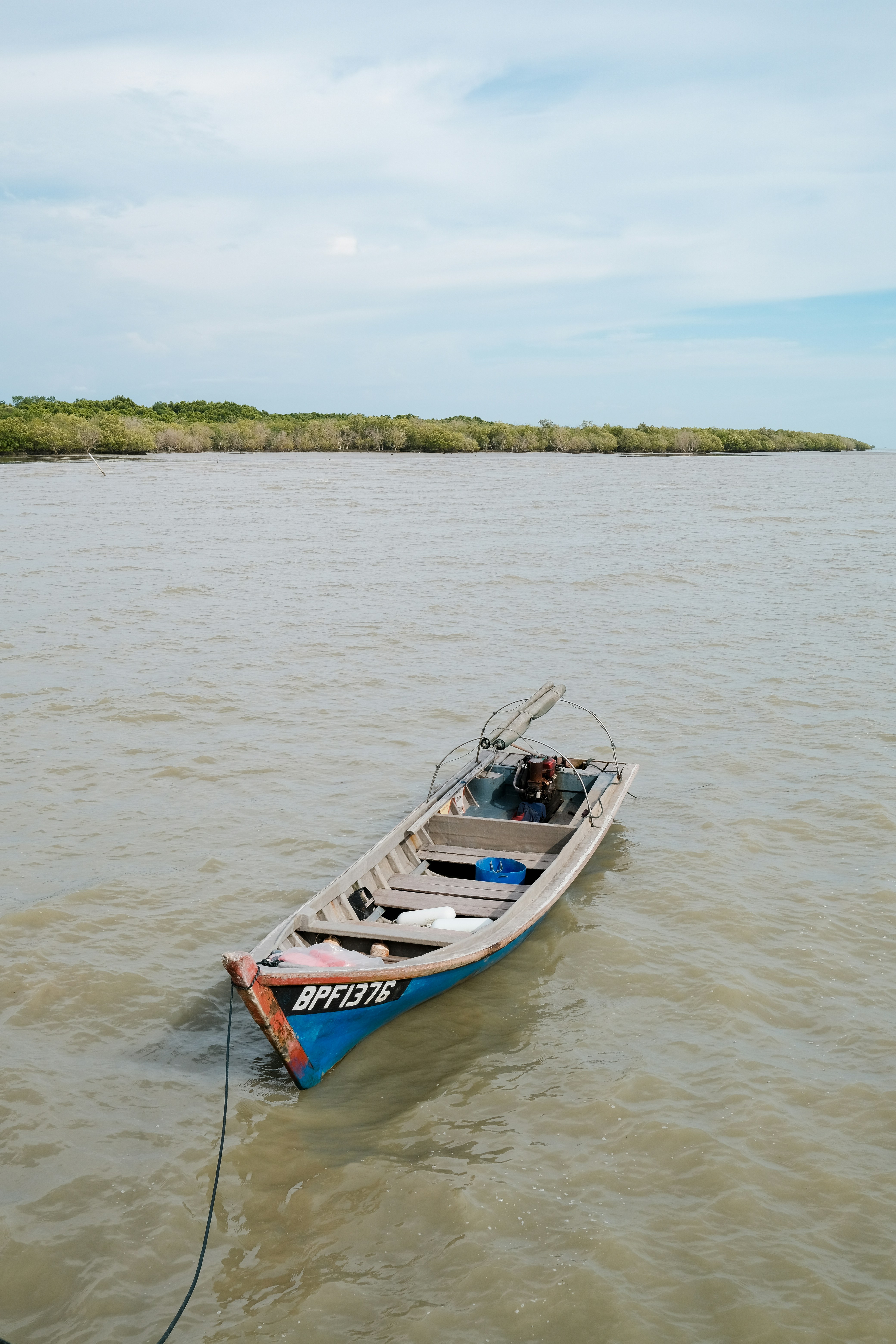 Quiet Estuary: A Blue Boat Anchored in Pale Tidal Waters