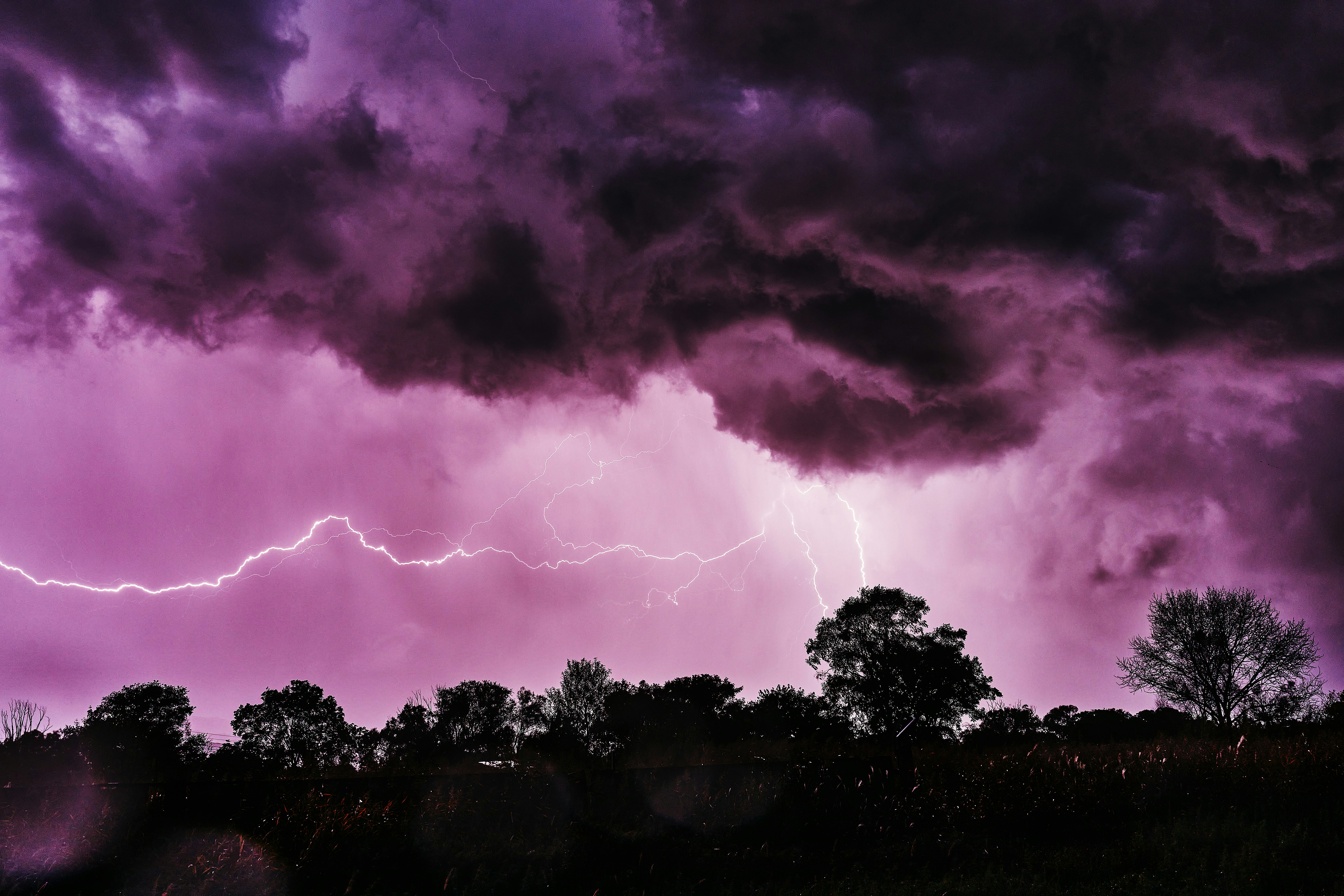 A purple sky with a lightning bolt in the distance photo – Free ...