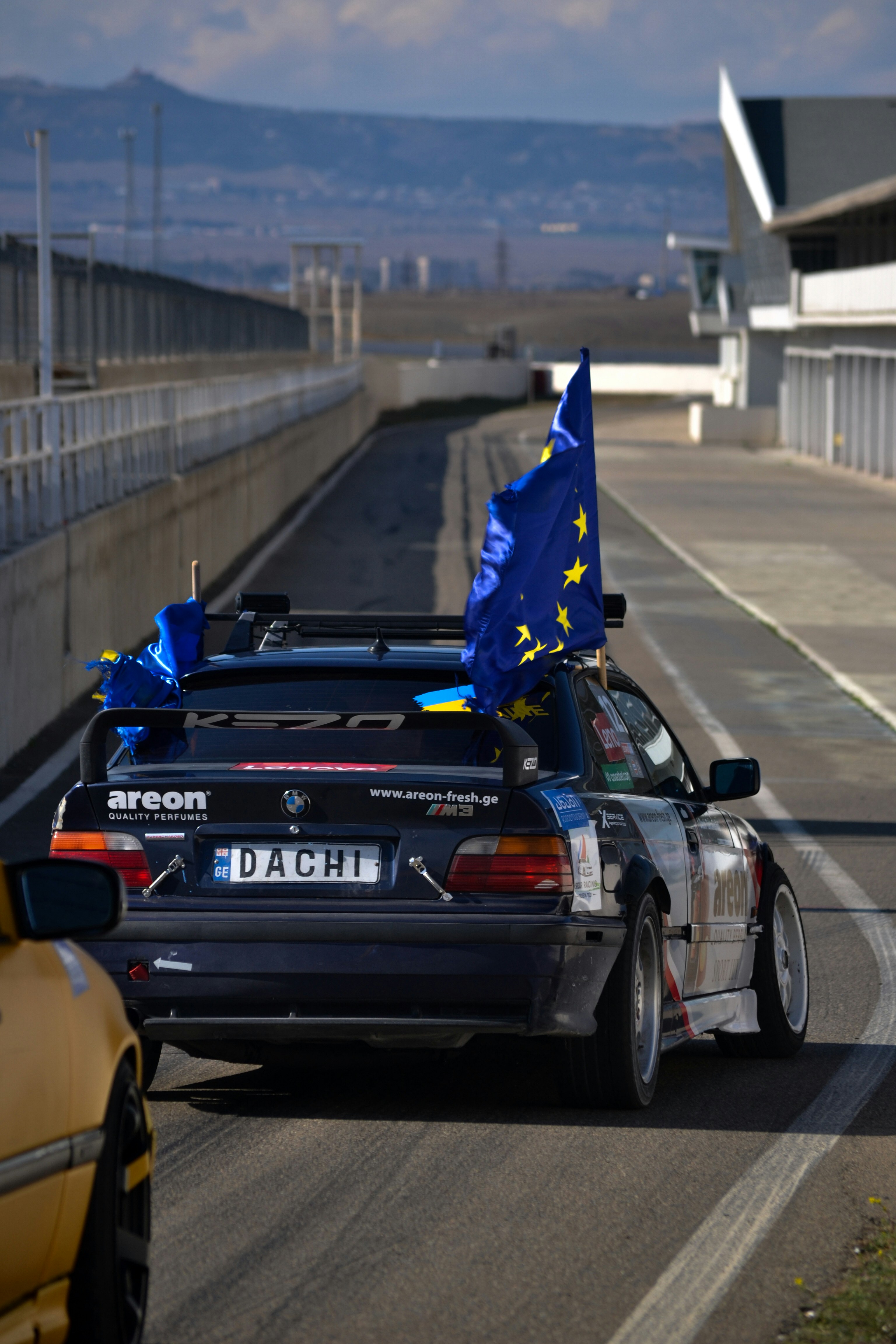 Foto zum Thema Ein Auto, das eine Straße mit einer Flagge darüber fährt ...