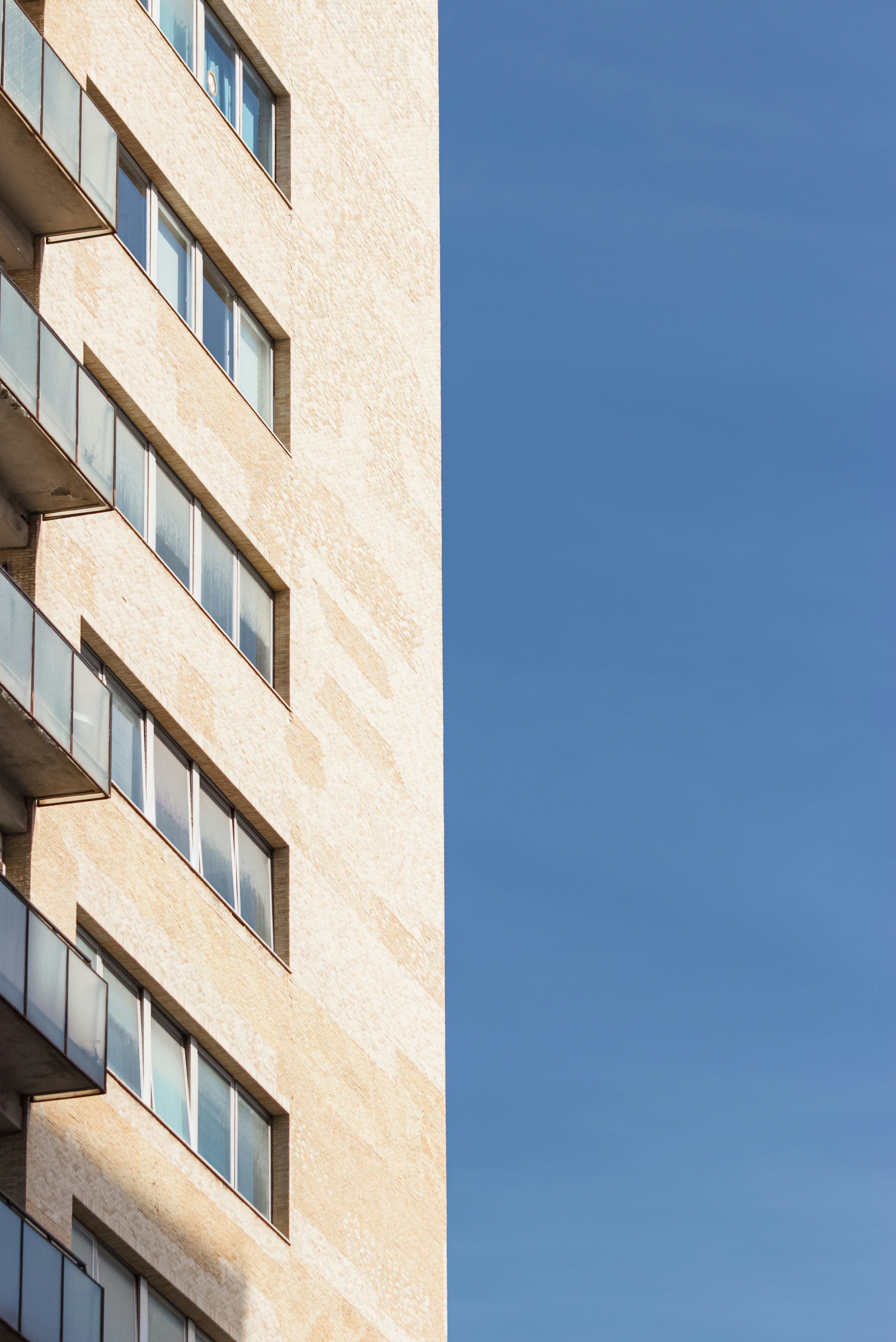 A tall building with windows and a sky background photo – Free Blue ...
