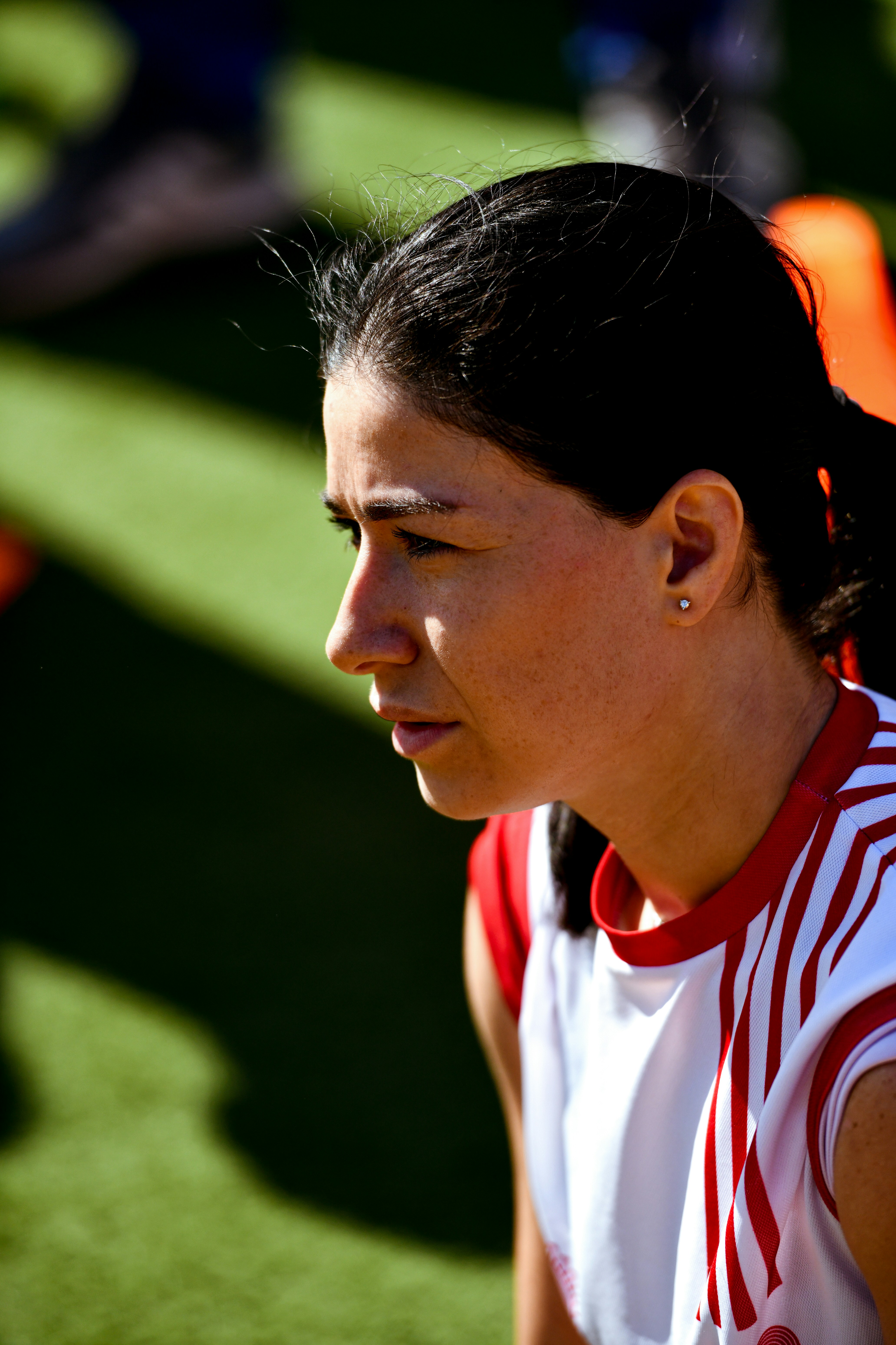 Focused Gaze: A Female Athlete in Profile Against a Vibrant Field