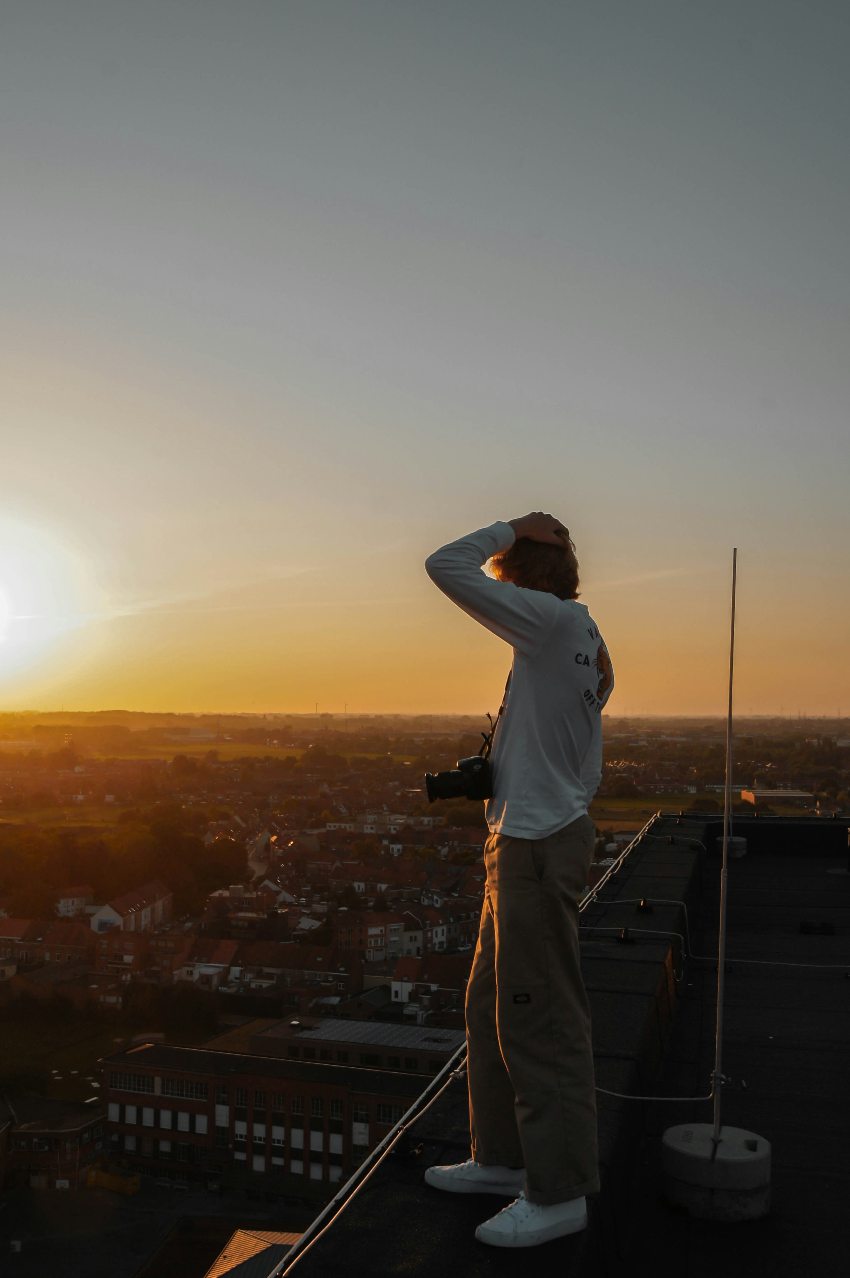 A man standing on top of a roof next to a tall building photo – Free ...