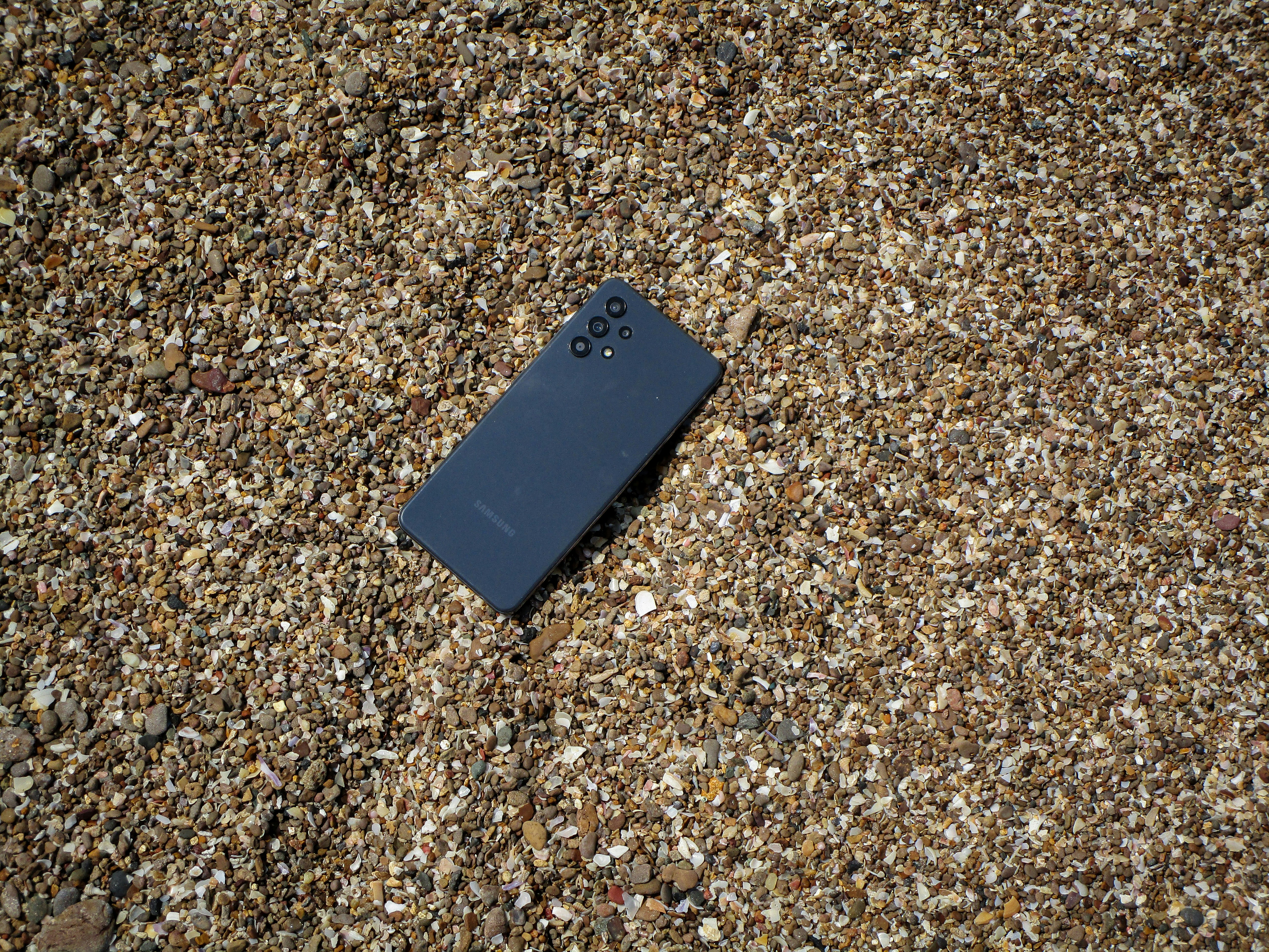 A cell phone laying on the ground covered in sand photo – Free Mumbai ...