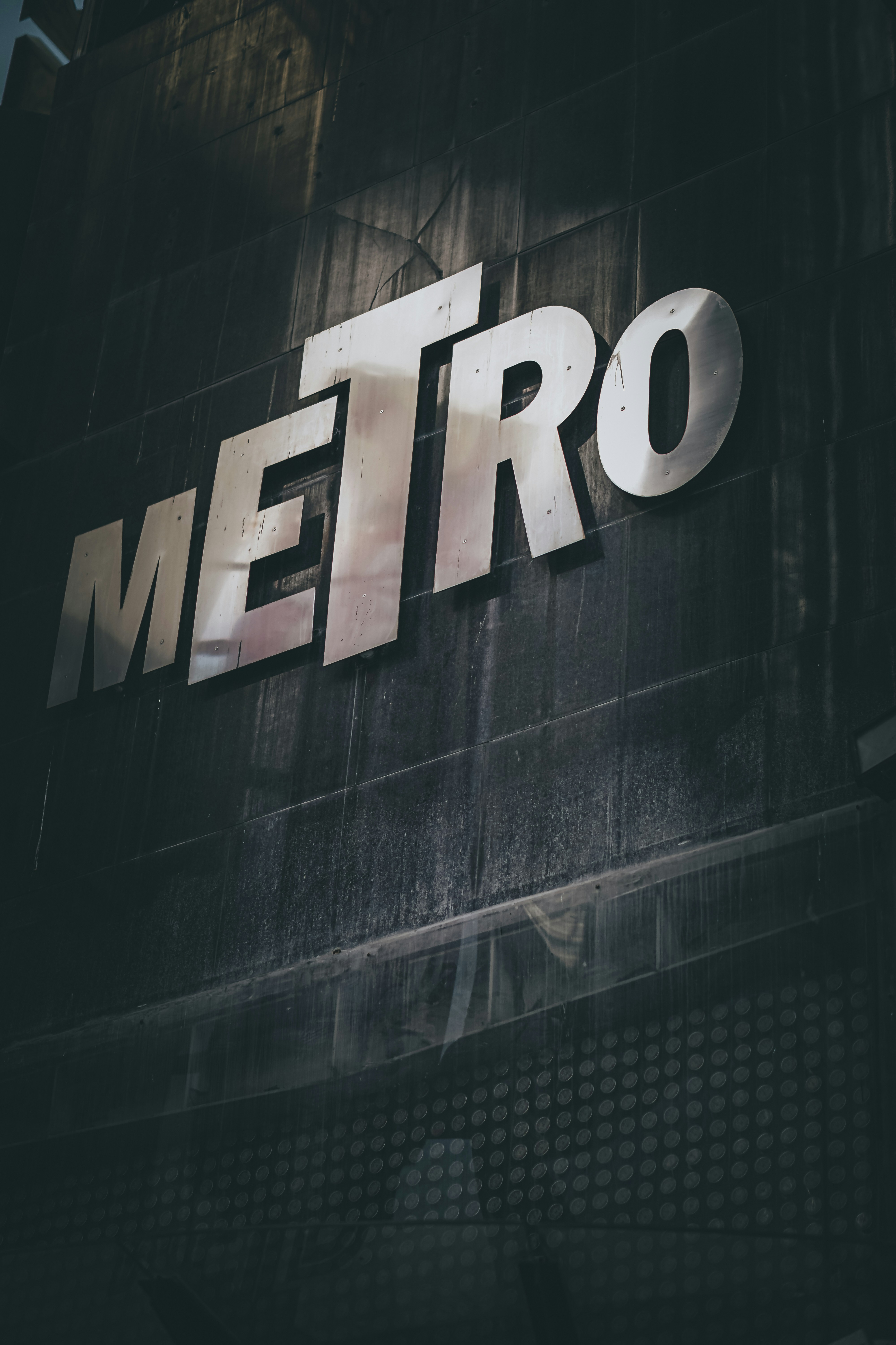 Metallic 'METRO' sign mounted on a dark, textured wall, reflecting urban architecture's industrial essence.