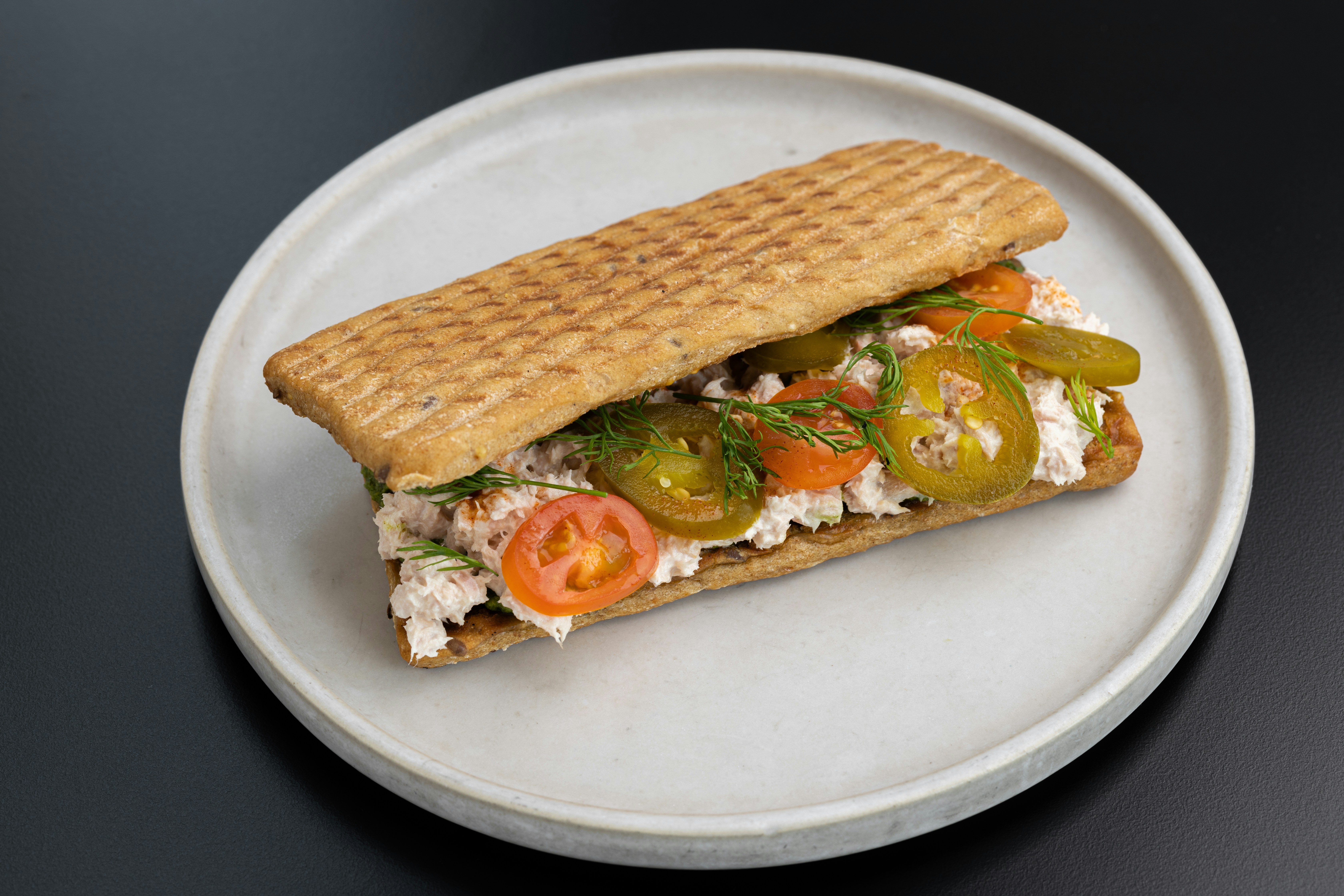 Une assiette blanche surmontée d’un sandwich sur le dessus d’une table ...