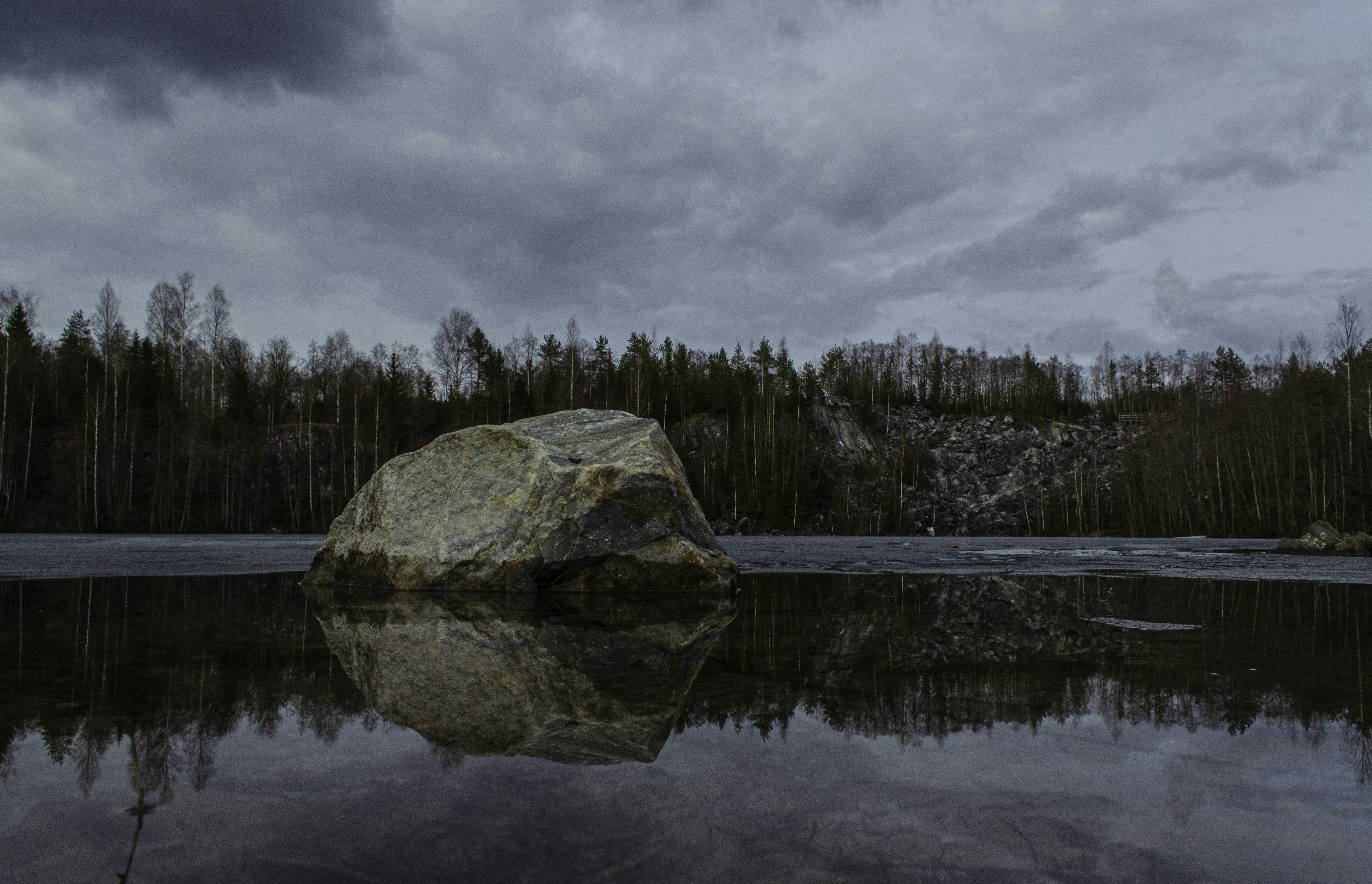 Solitary Boulder Mirrors a Glassy Lake Beneath a Brooding Sky