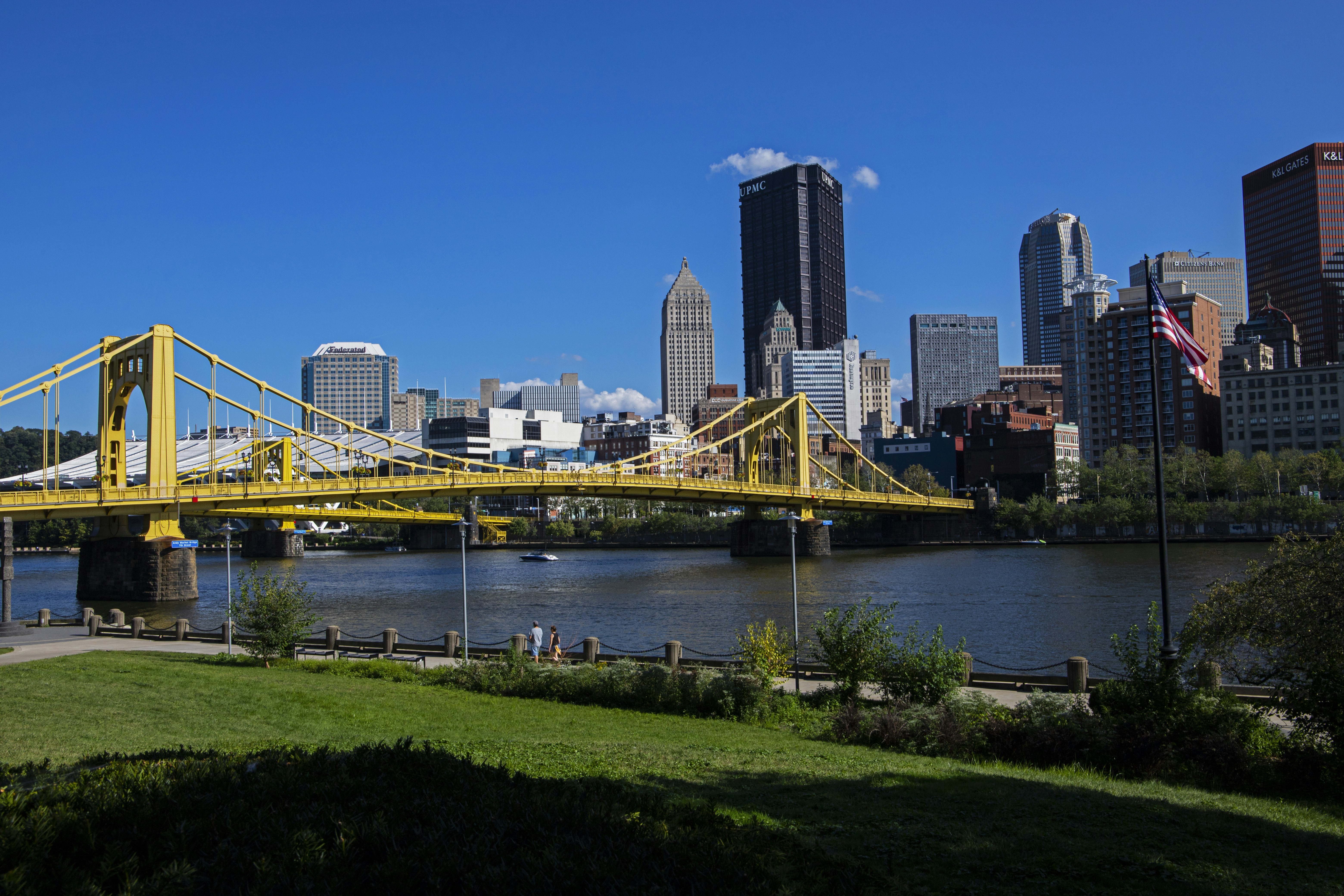 A yellow bridge over a river with a city in the background photo – Free ...