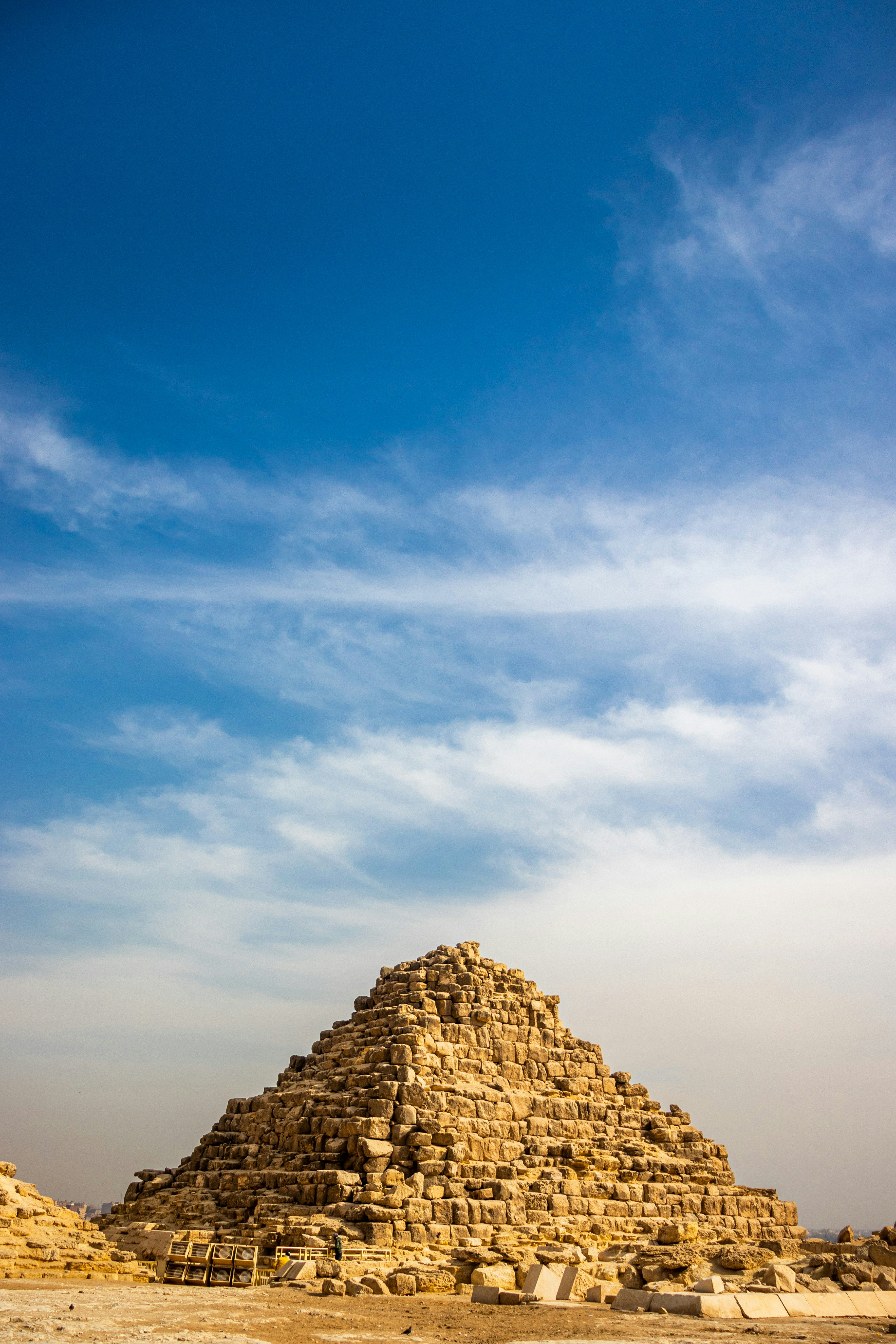 The remnants of a pyramid rise against a vibrant blue sky, showcasing the ancient architectural prowess and the passage of time.