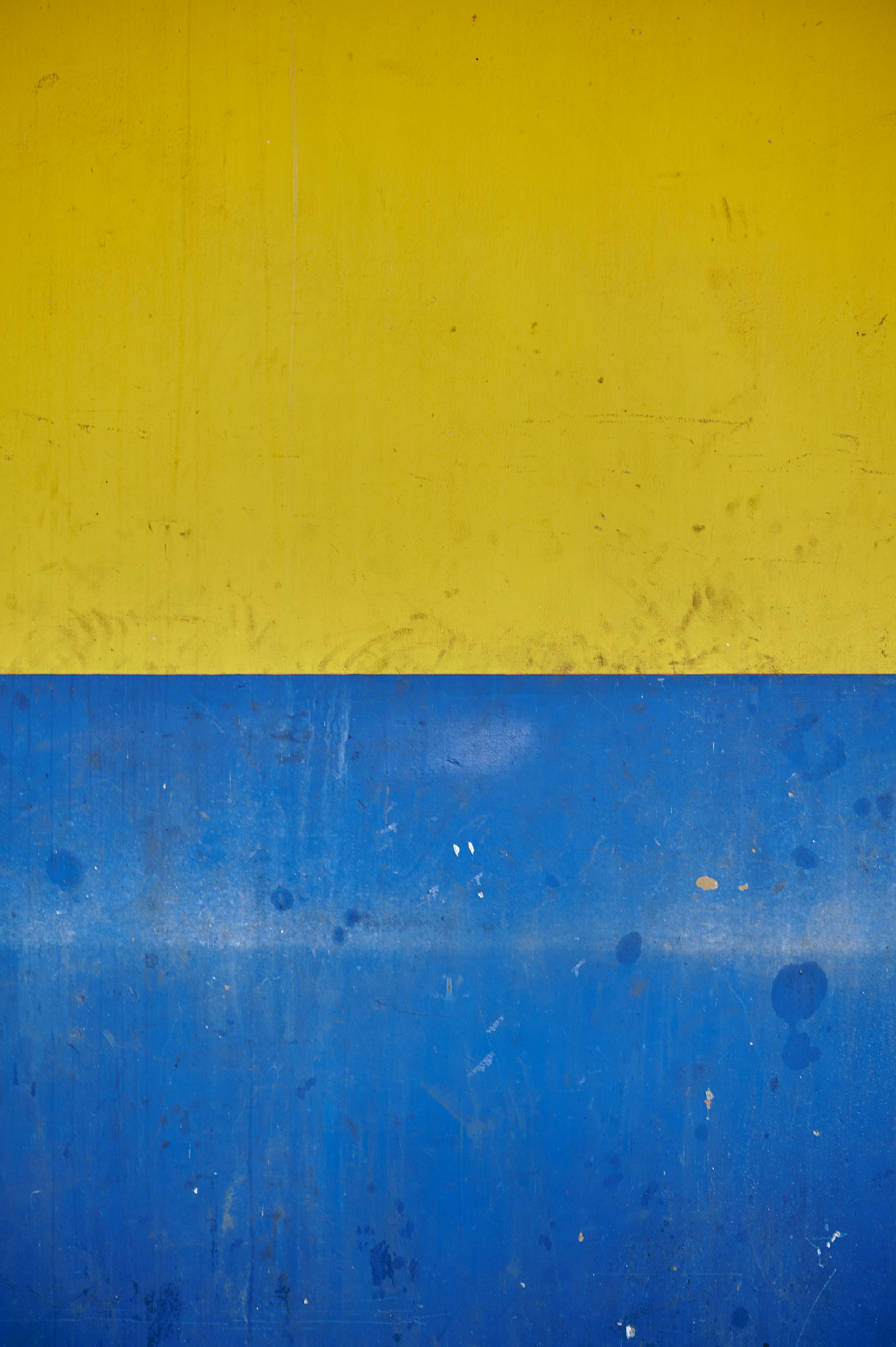 Horizontal split of vibrant yellow and blue surfaces, showcasing texture and subtle imperfections.