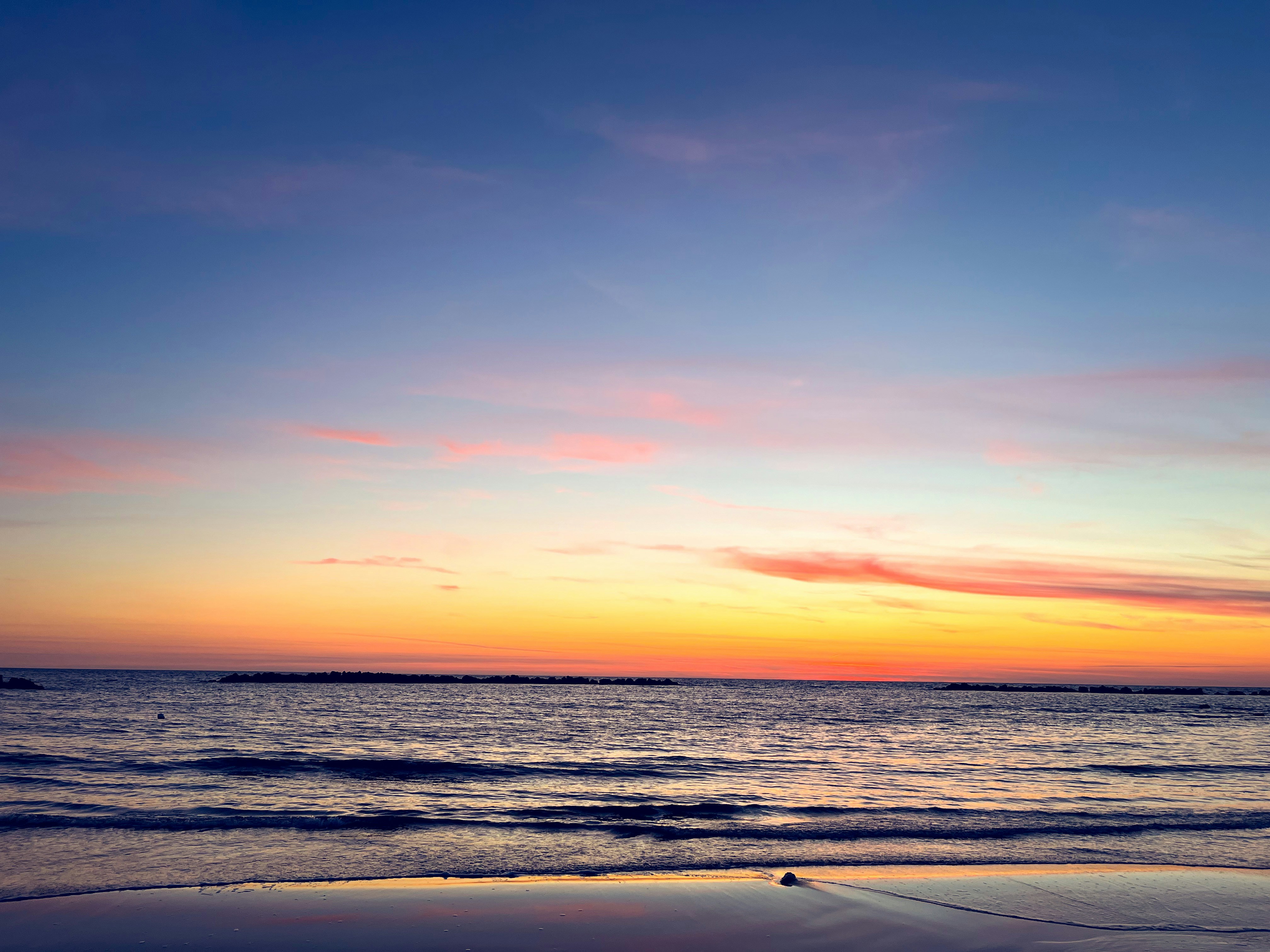 Foto El sol se está poniendo sobre el océano en la playa – Imagen Ancio ...