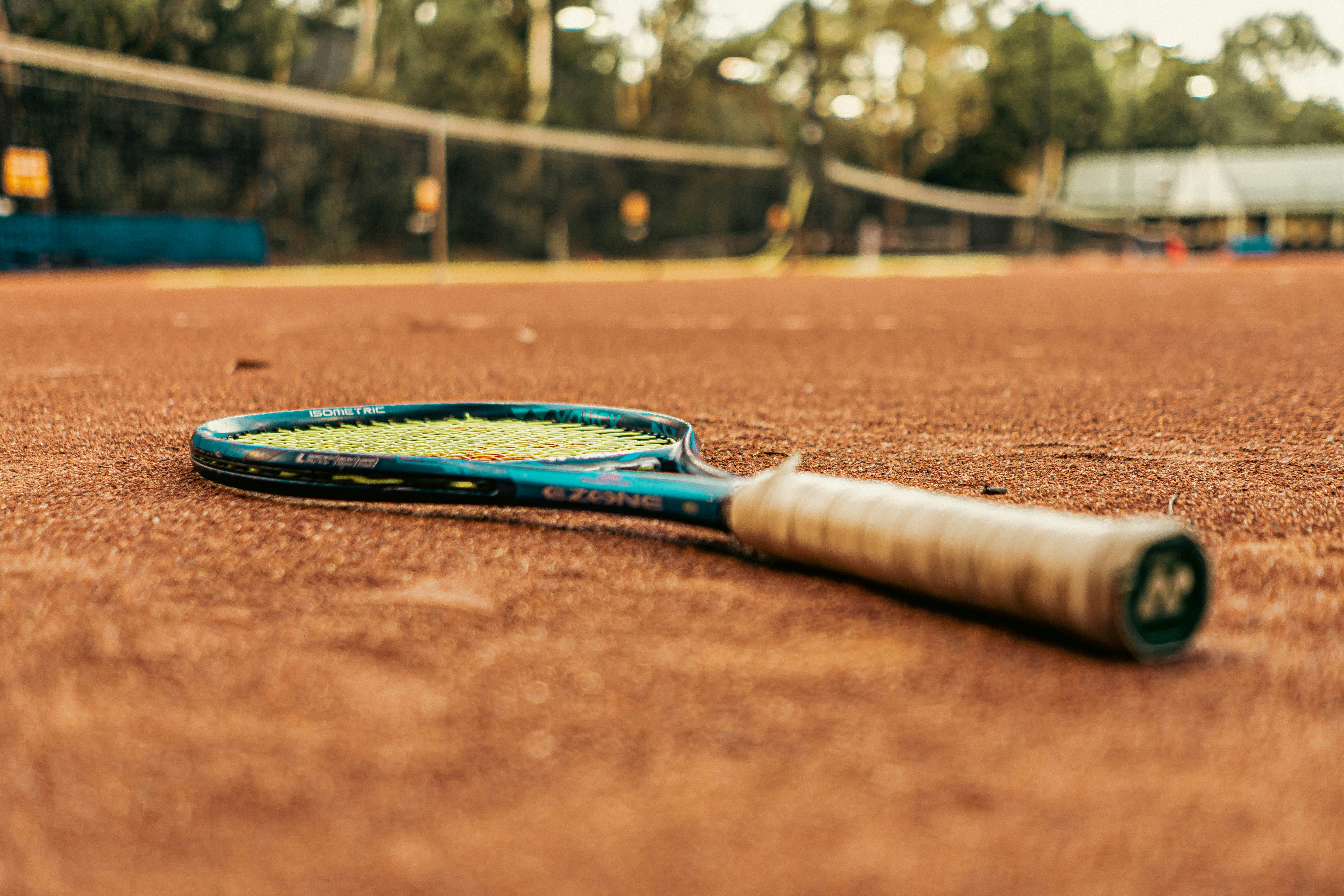 A tennis racket laying on a tennis court photo – Free Racket Image on ...