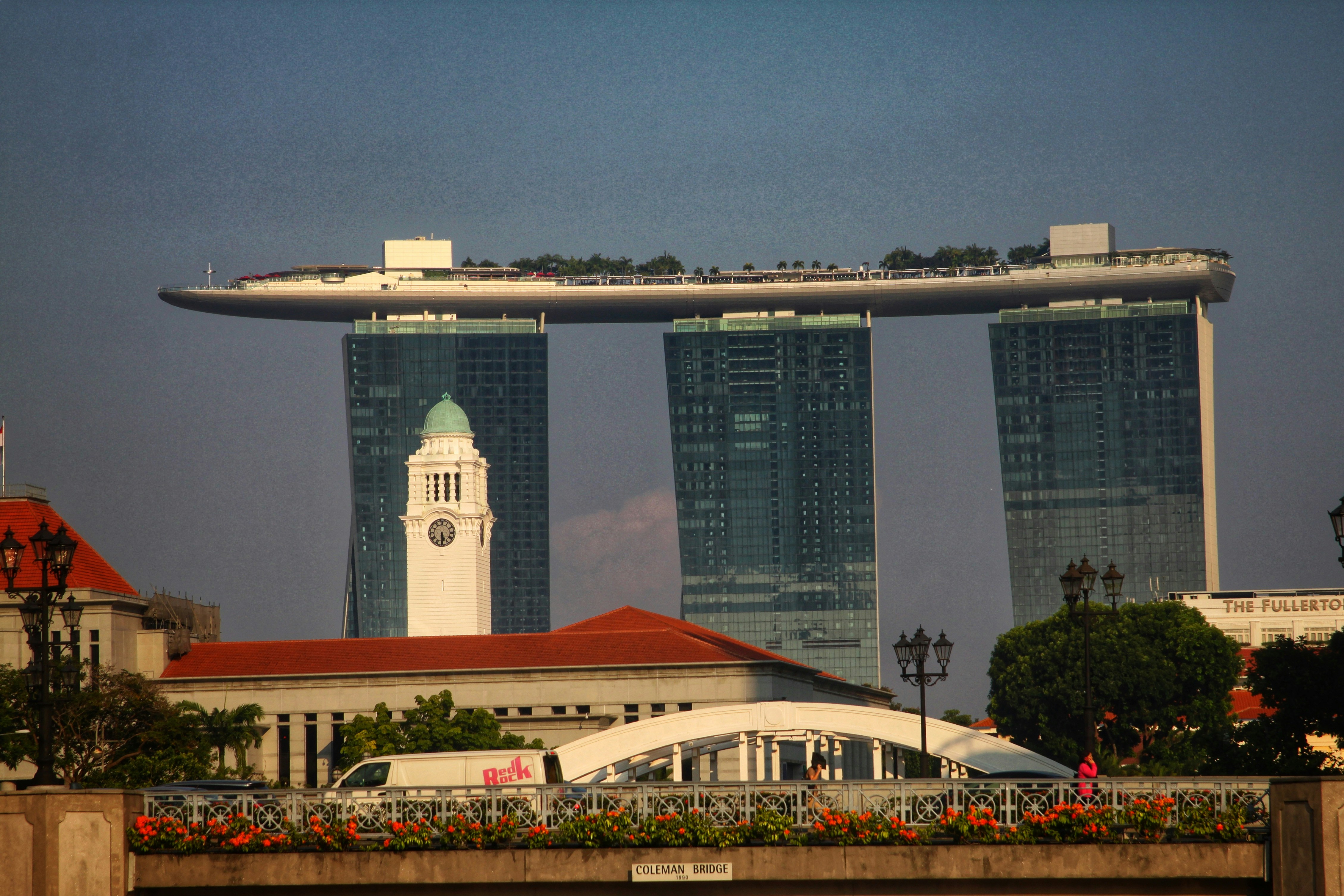 A futuristic structure floats above two towering skyscrapers, showcasing innovative design against a clear sky. The scene captures the essence of modern urban architecture.