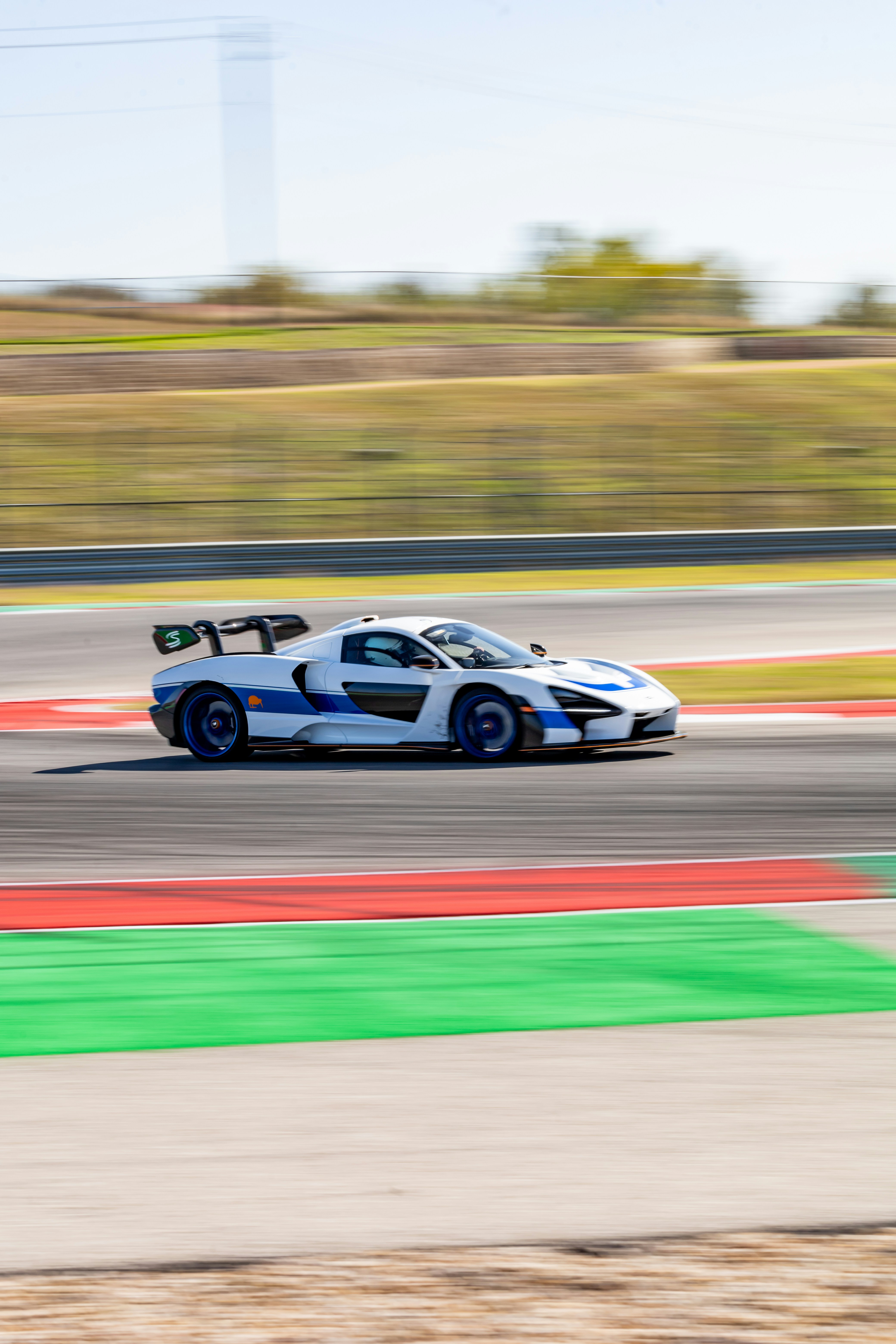 A white and blue race car driving on a track photo – Free Car Image on ...