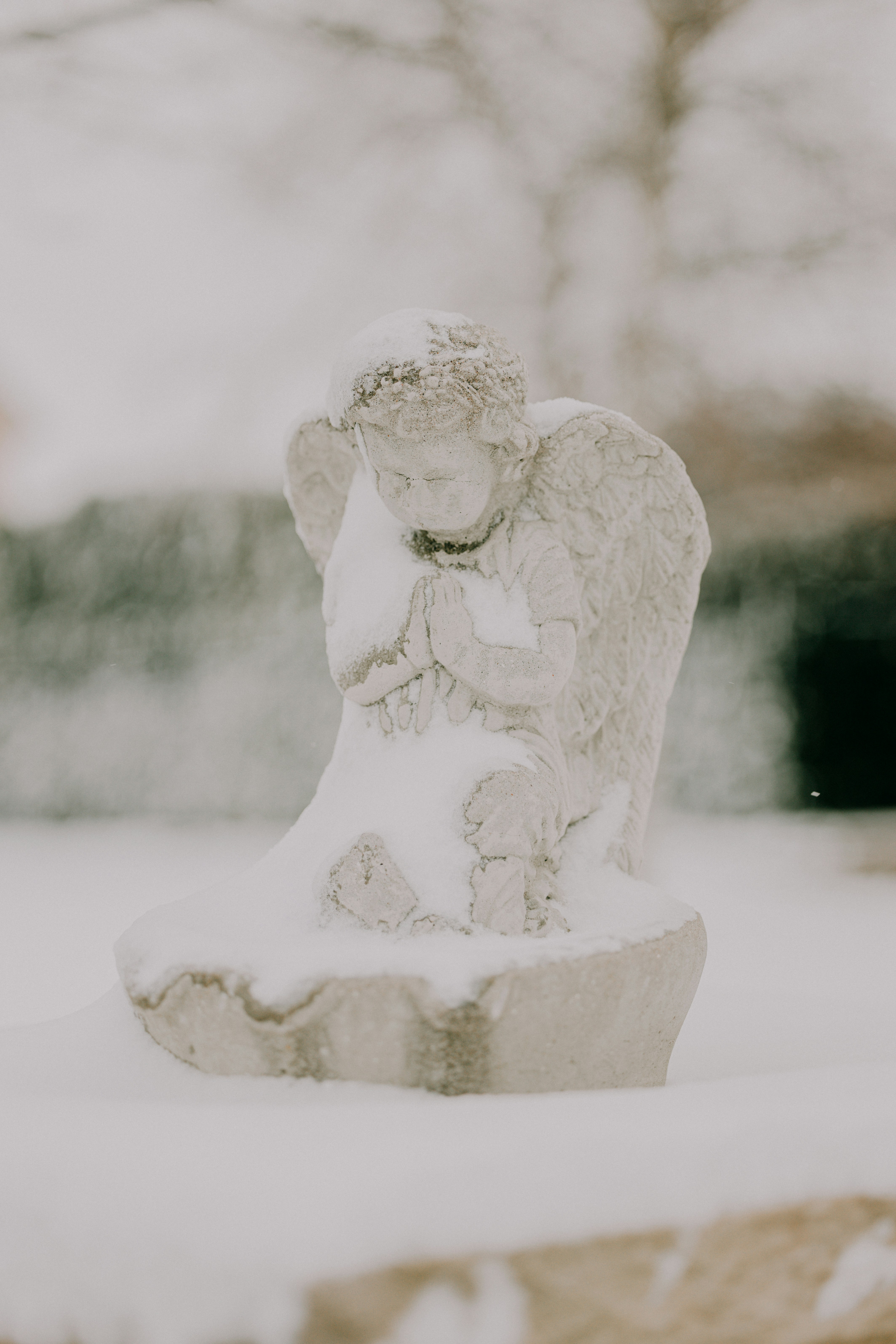 A statue of an angel sitting in the snow photo – Free Grey Image on ...