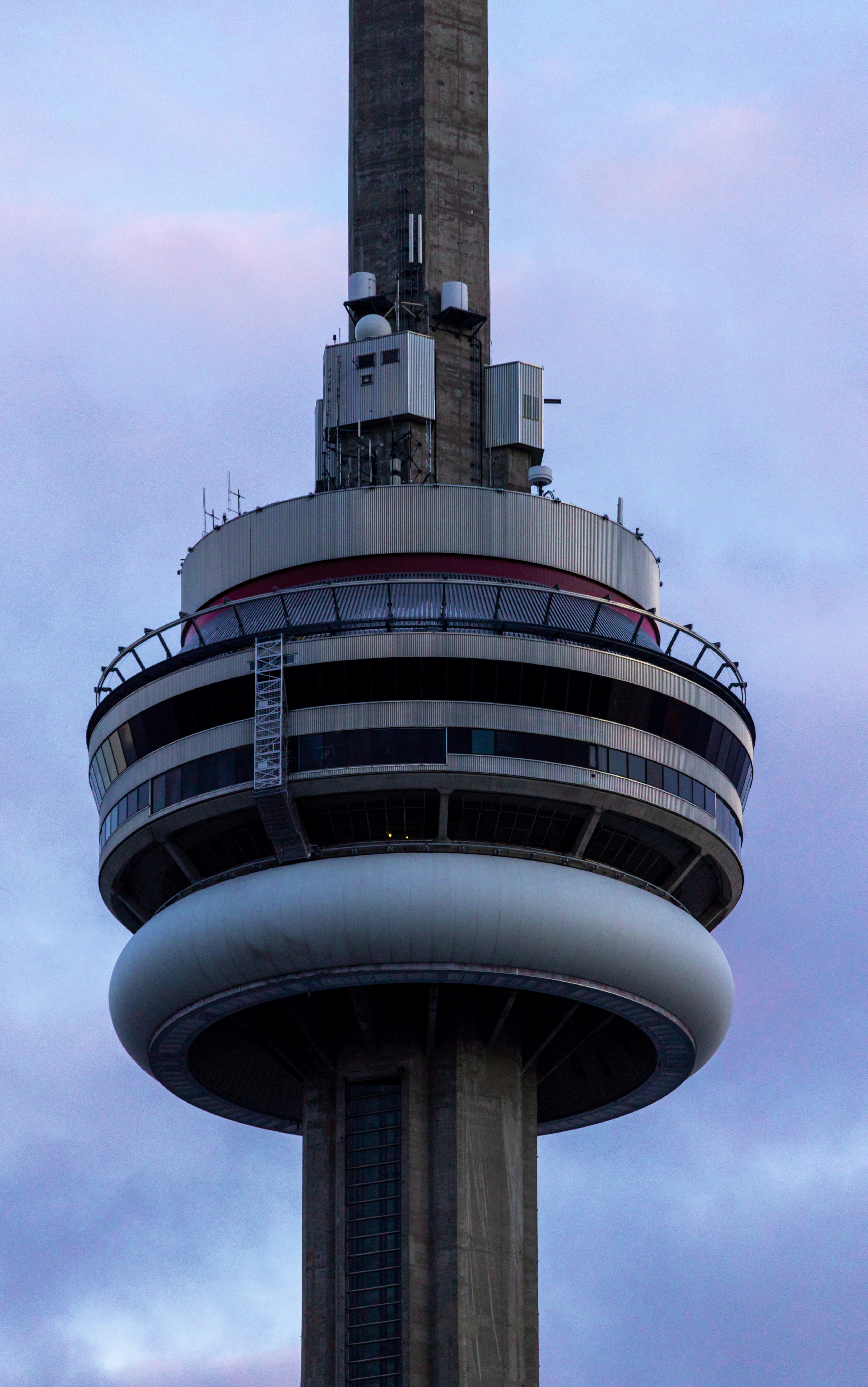 Close-up of a tower's observation deck and communications equipment against a cloudy sky.