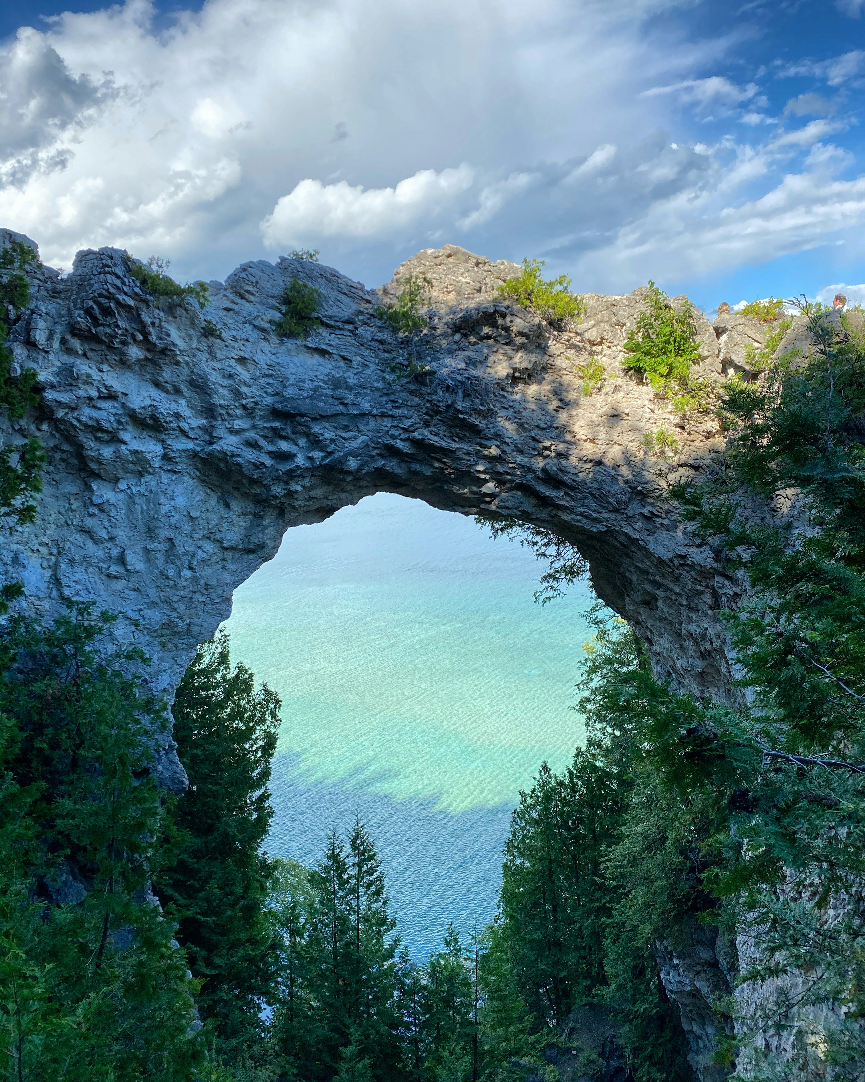 A large rock arch over looking a body of water photo – Free Nature ...