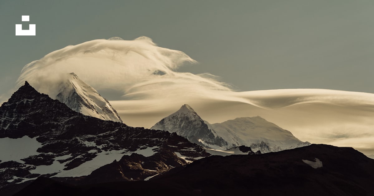 Une Montagne Couverte De Nuages Et De Neige Sous Un Ciel Bleu Photo