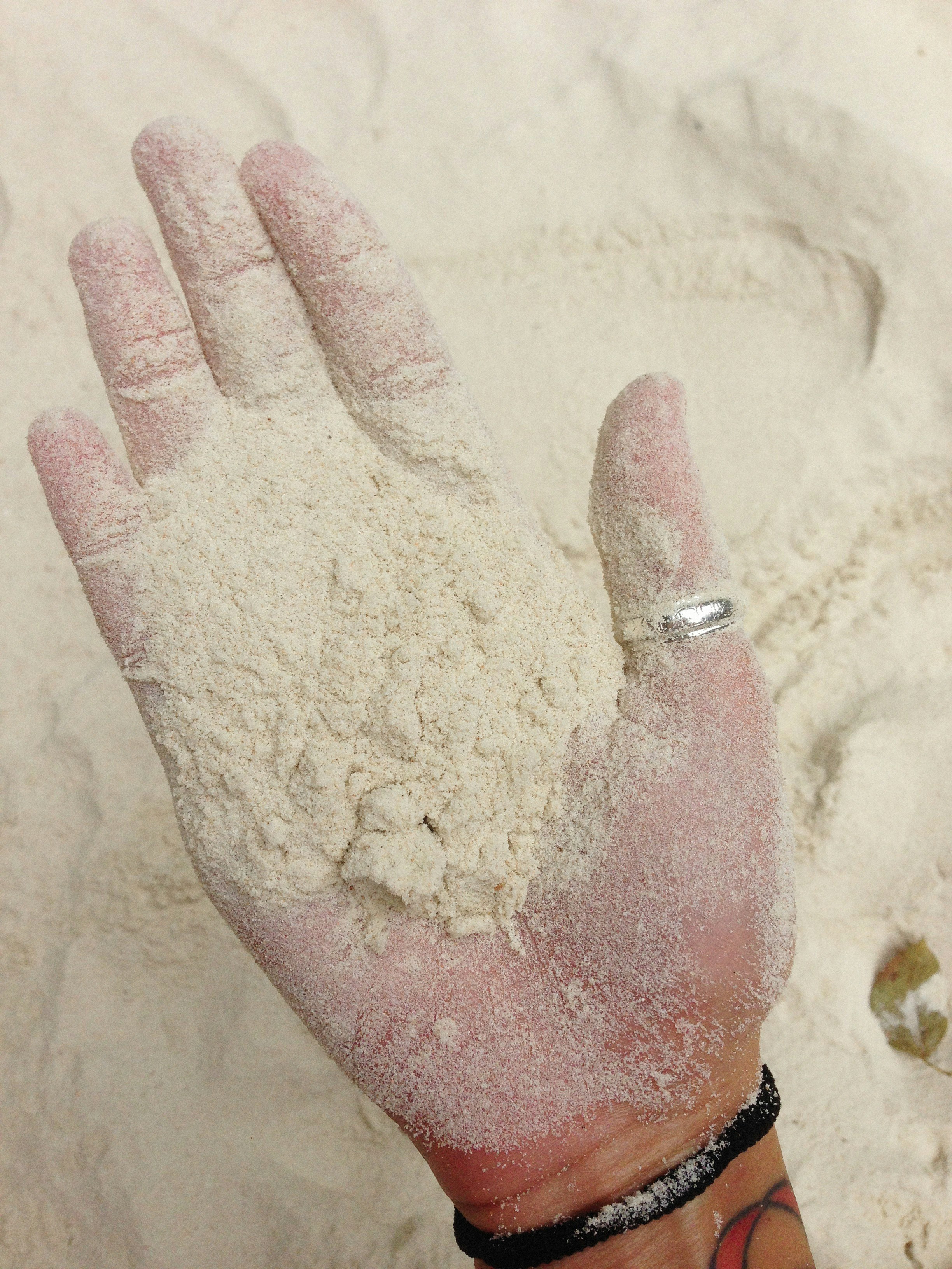 a hand with a ring on it covered in sand