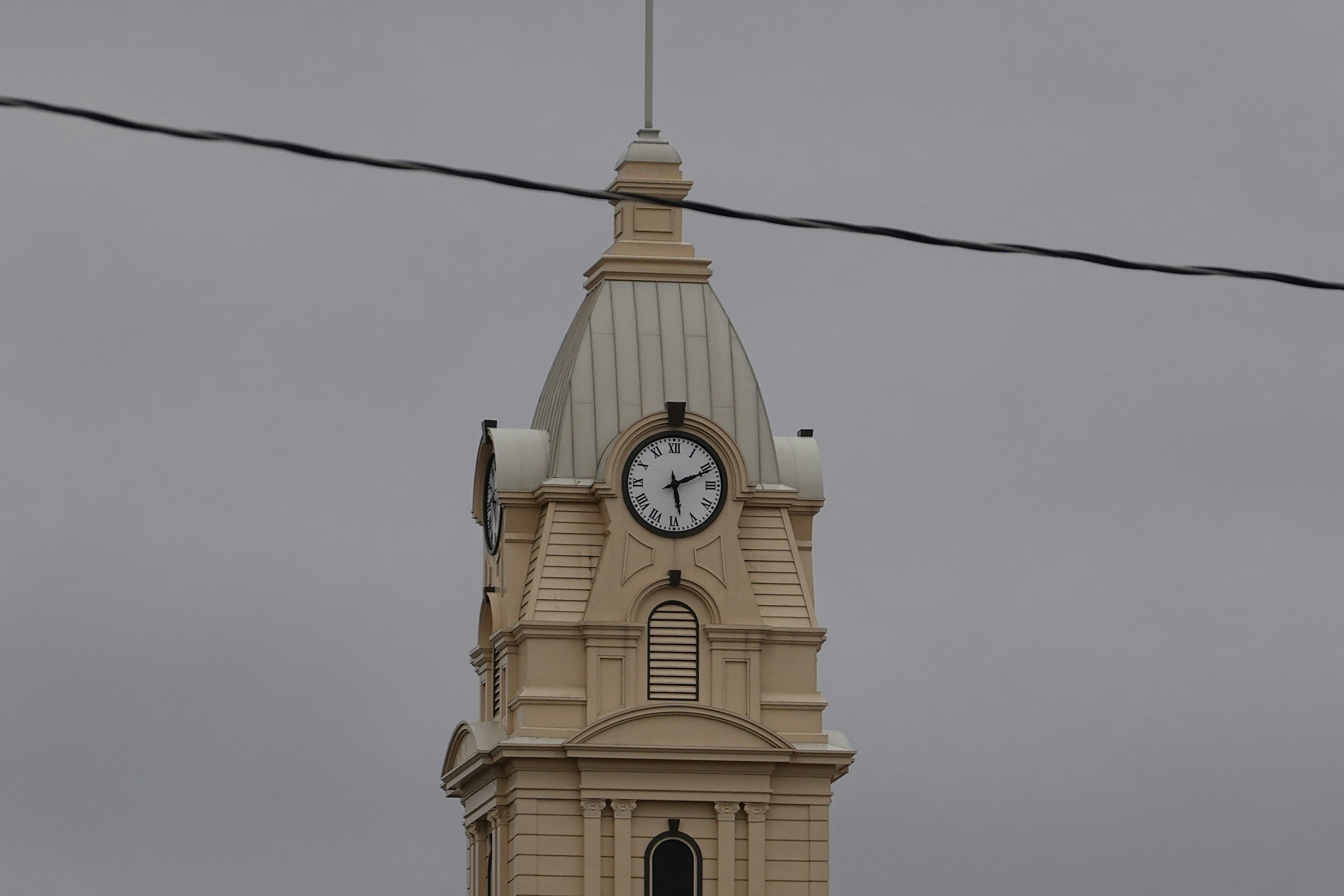 Historic clock tower with intricate architectural details and a visible clock face against a gray sky.