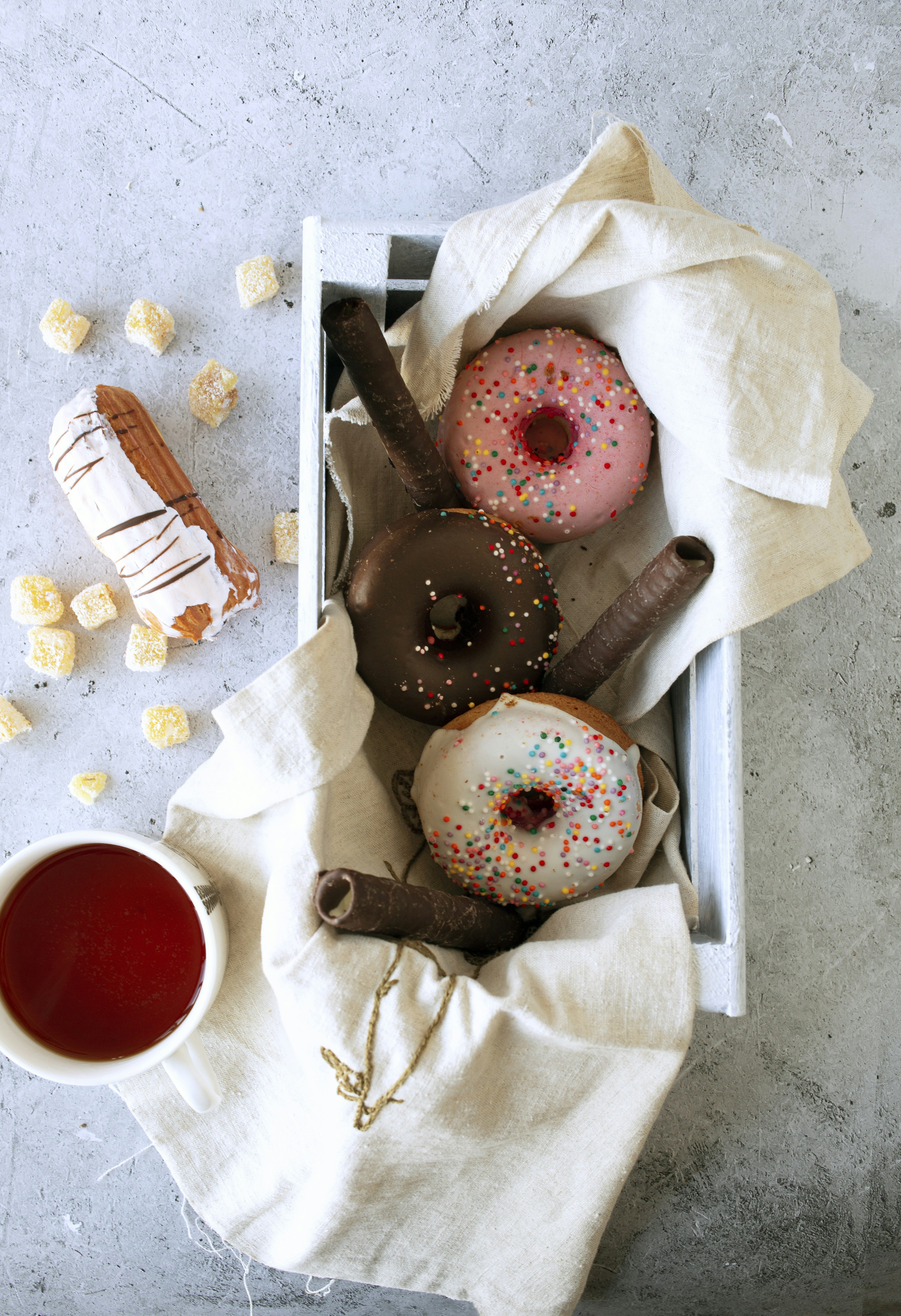Crate of Sprinkled Donuts: Cinnamon Sticks, Linen, and Red Tea