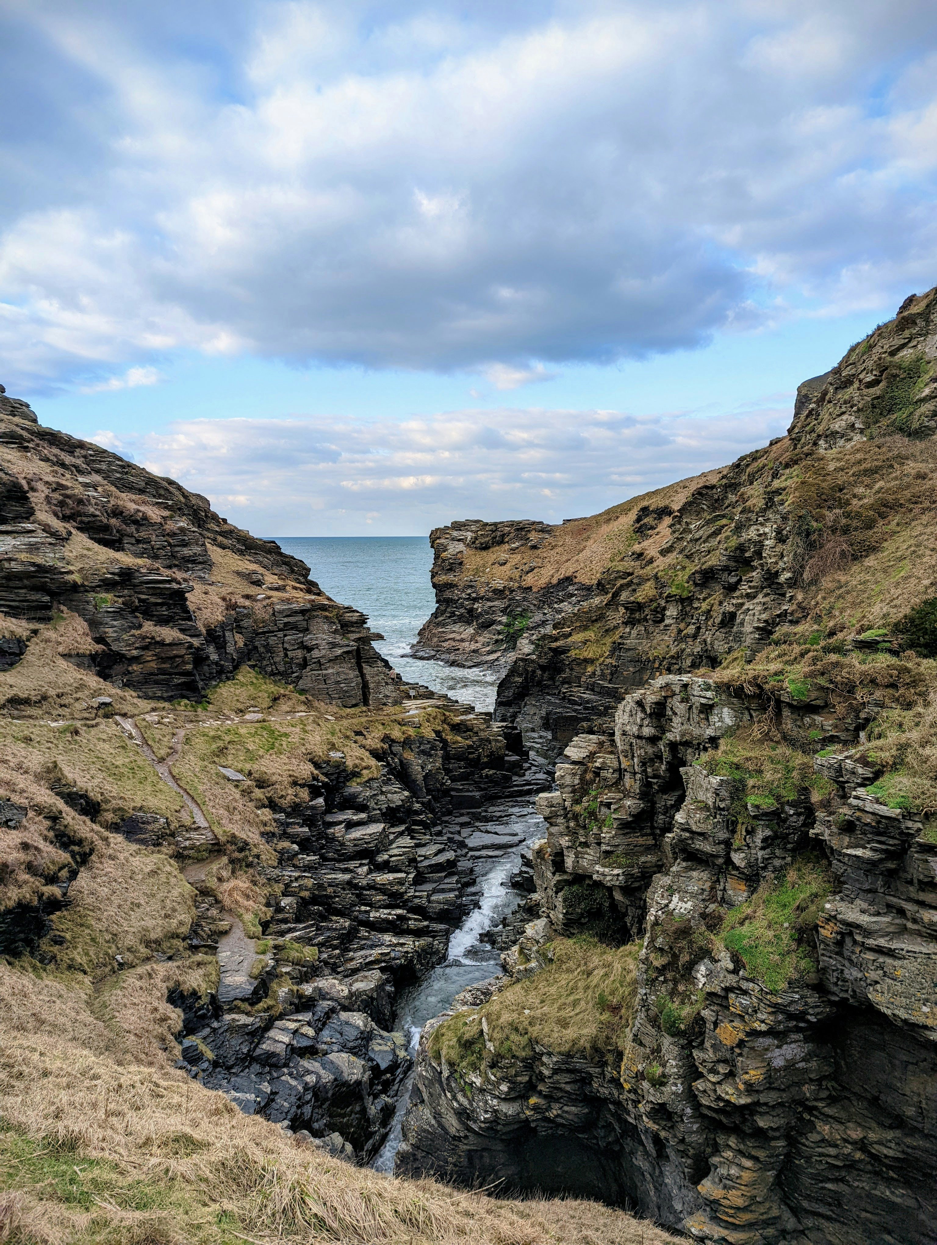 A rocky cliff with a small stream running through it photo – Free Sea ...