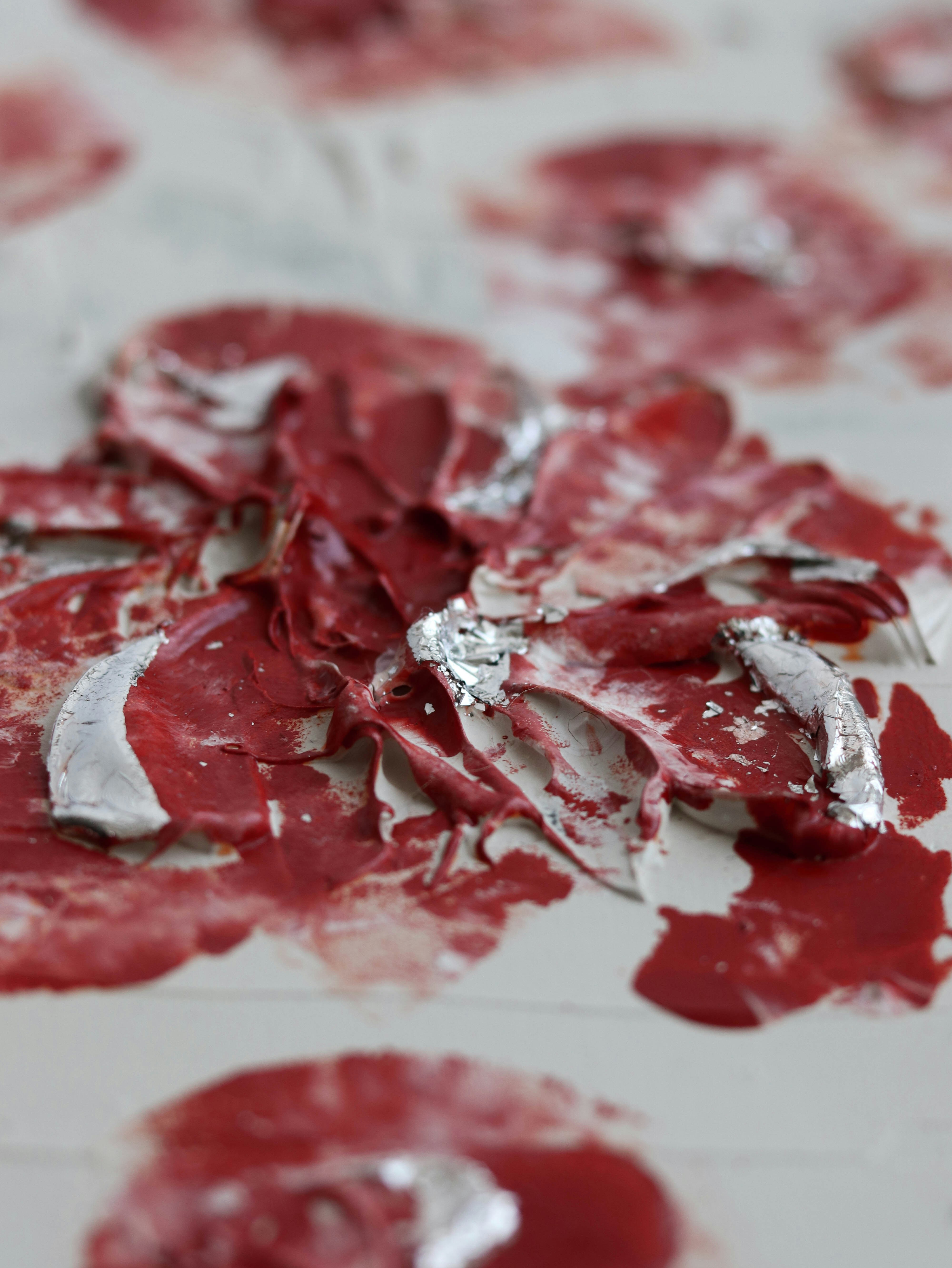 Crimson Petal Fragments on White: A Metallic Shard Still Life