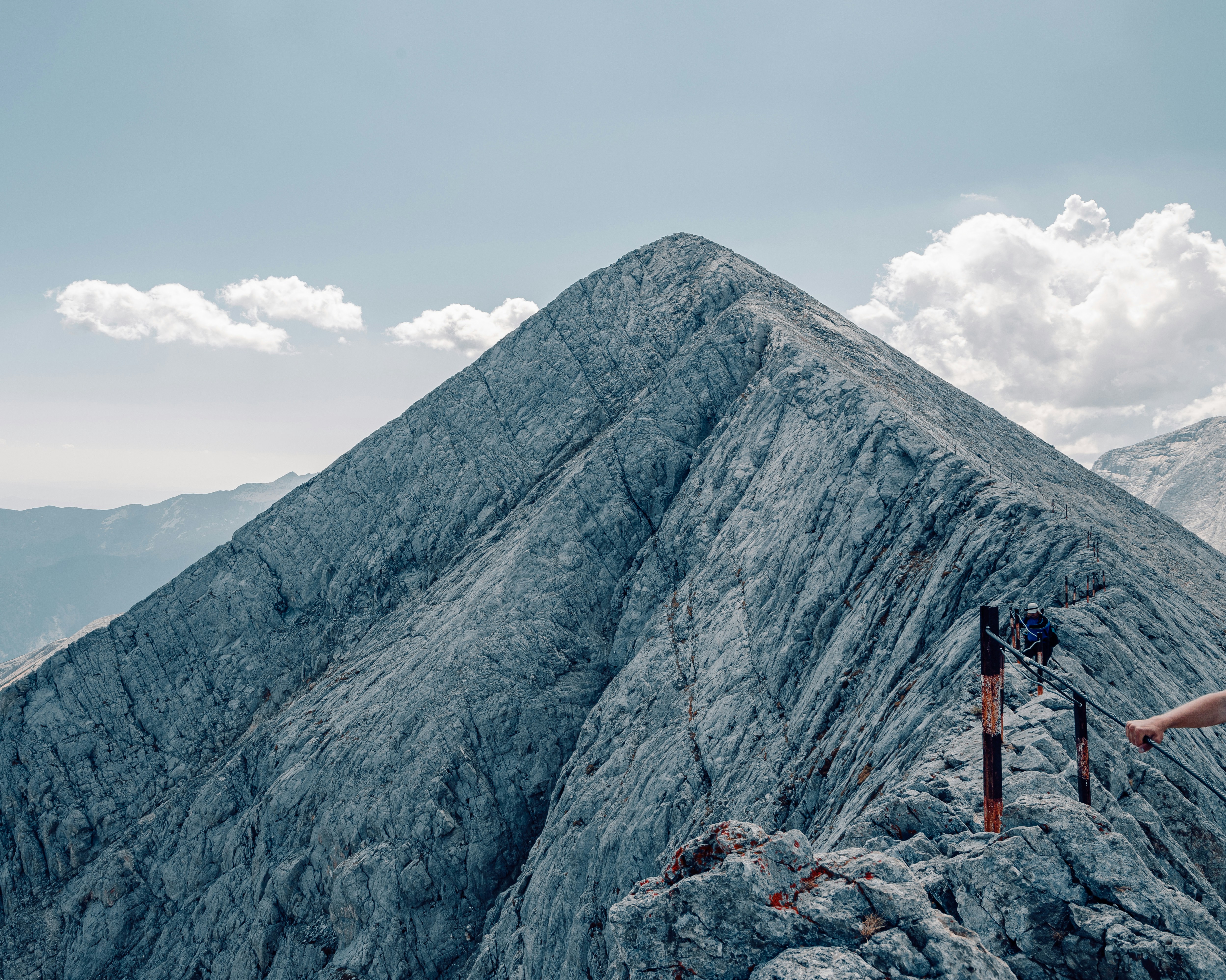 Jagged mountain peak under a blue sky with scattered clouds, showcasing the rugged beauty of nature's landscape.