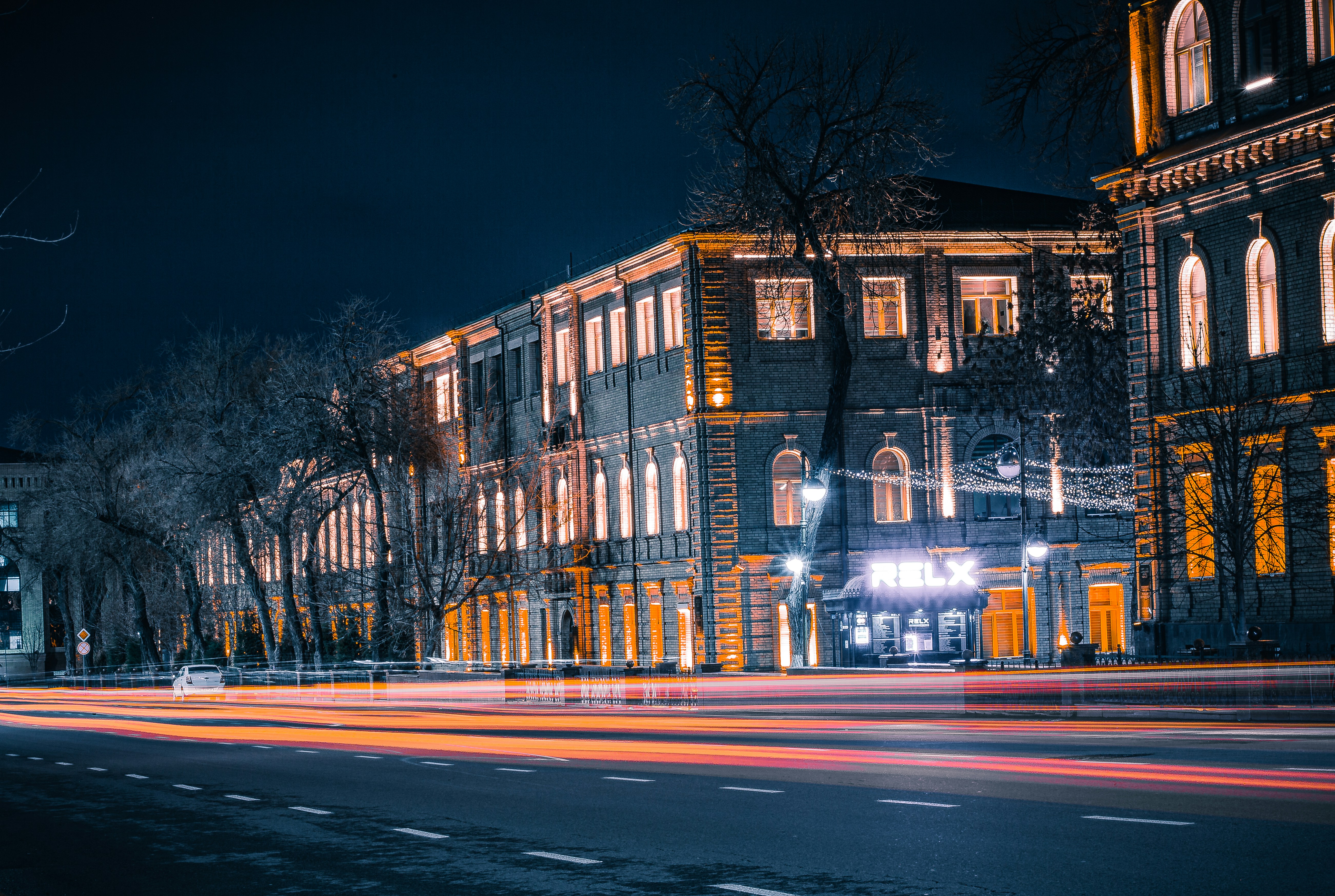 Historic building illuminated at night with light trails from passing vehicles.