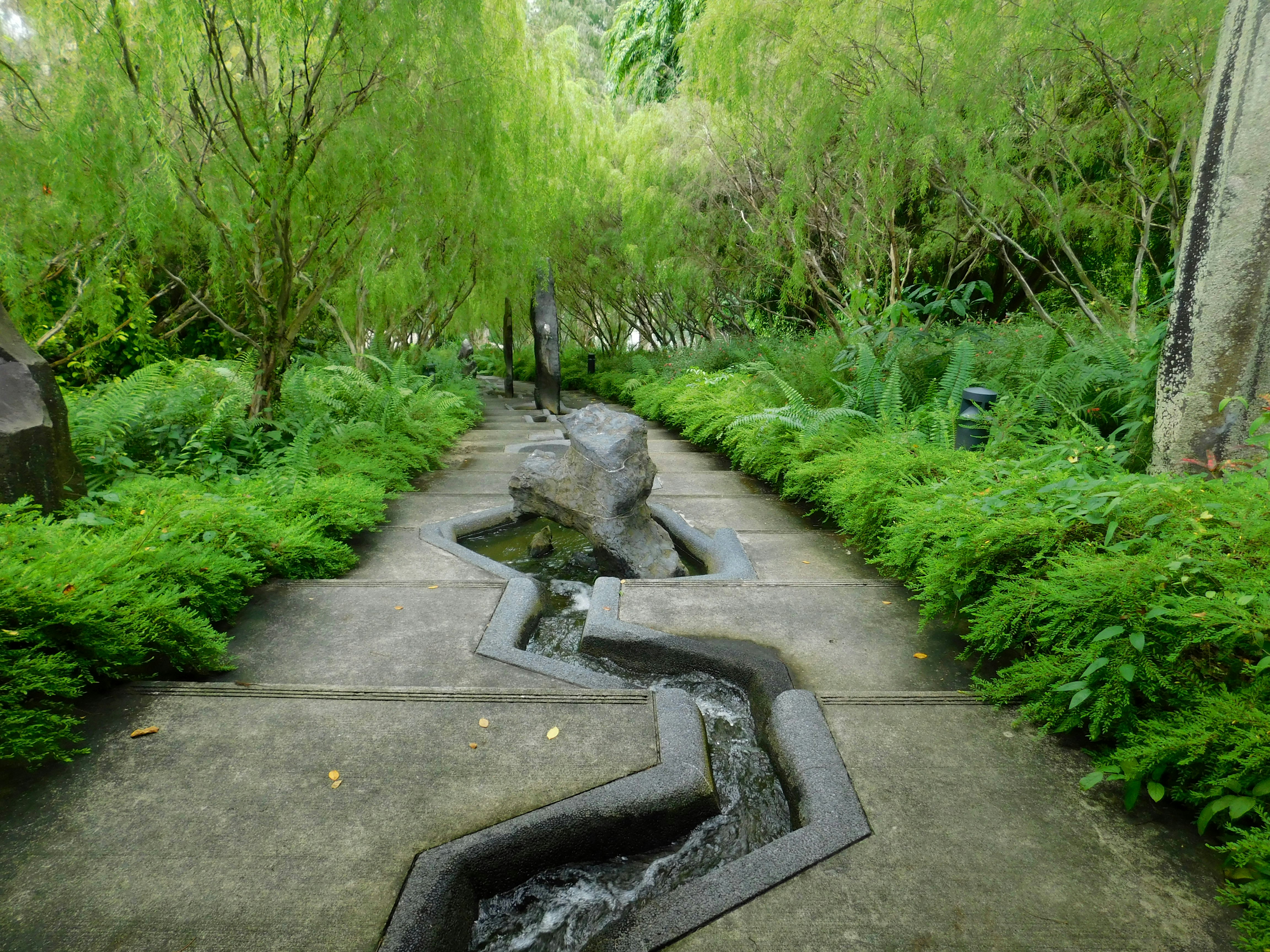 A small stream of water running through a lush green park photo – Free ...