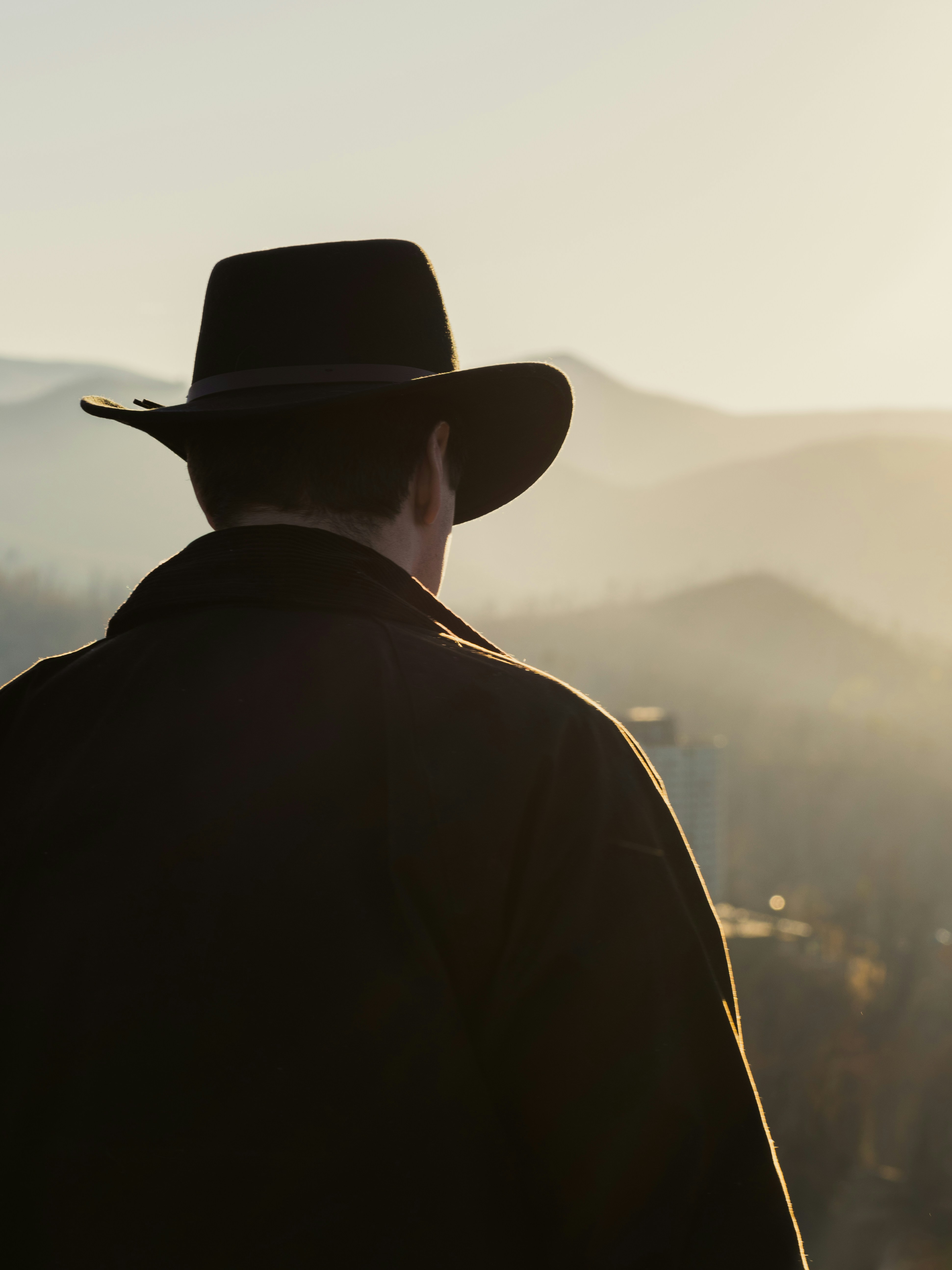 A man in a cowboy hat looking out over a mountain range photo – Free ...