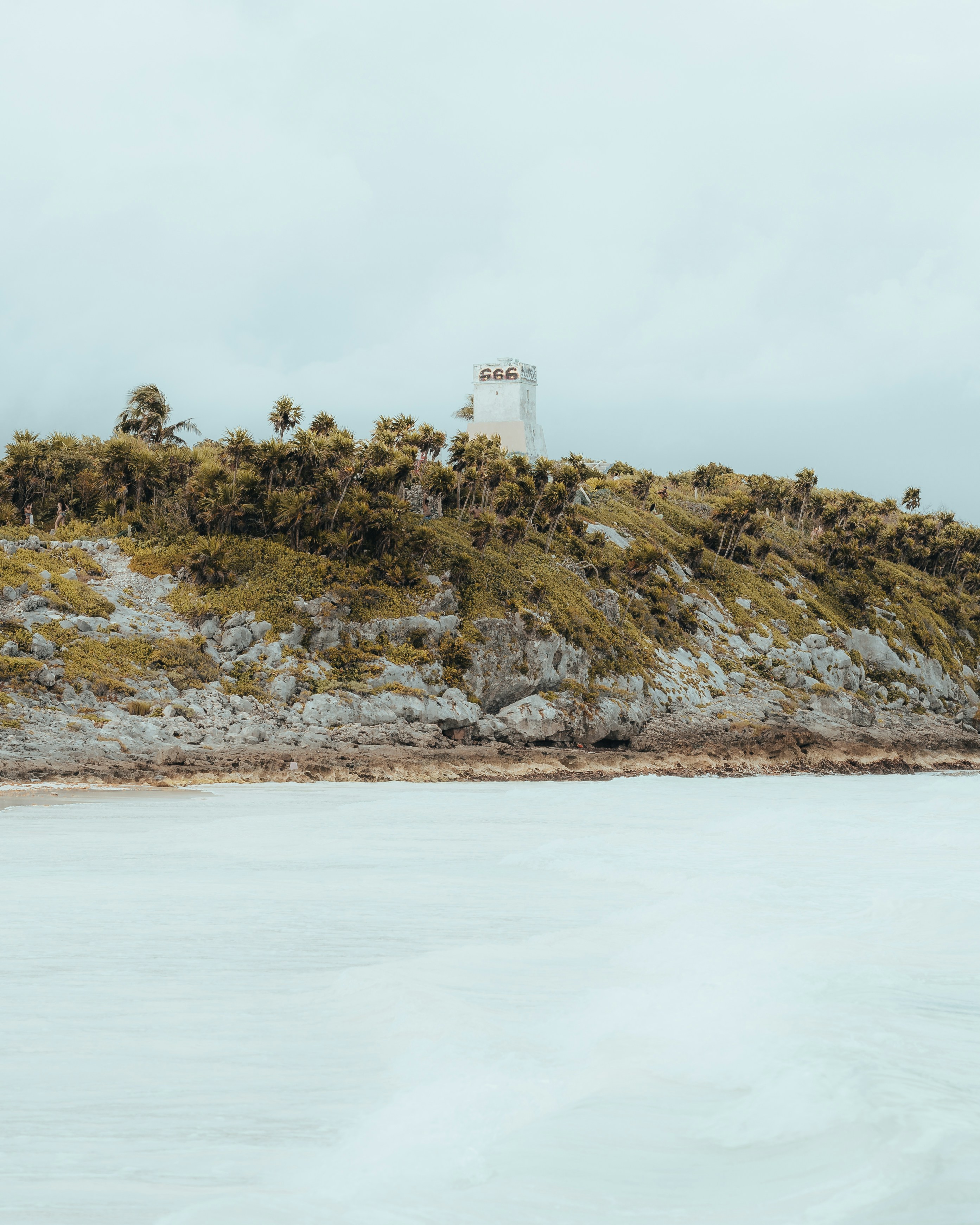 a light house on a hill with a body of water in front of it