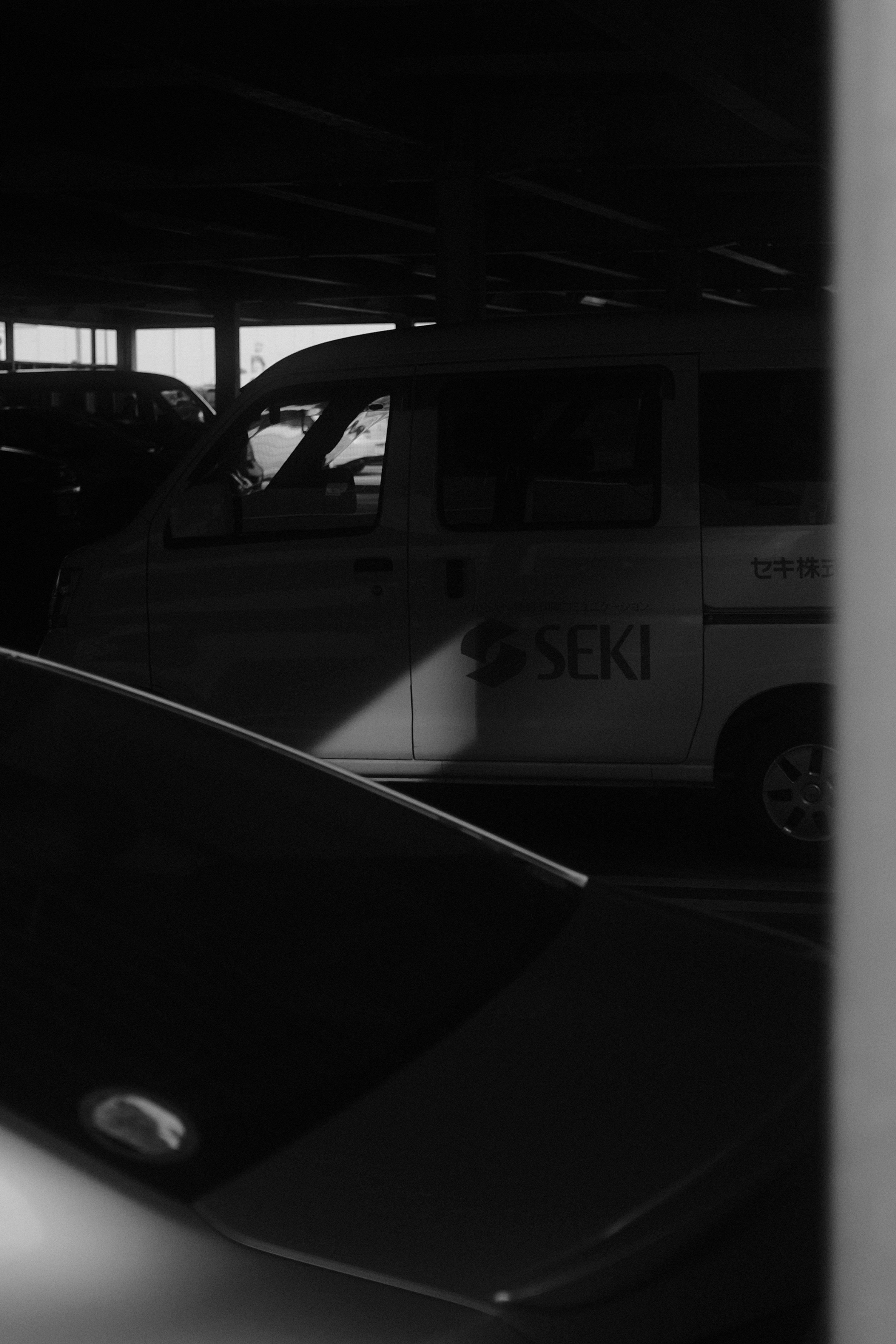 Shadowed Van, Concrete Sliver: A Parking-Garage Portrait