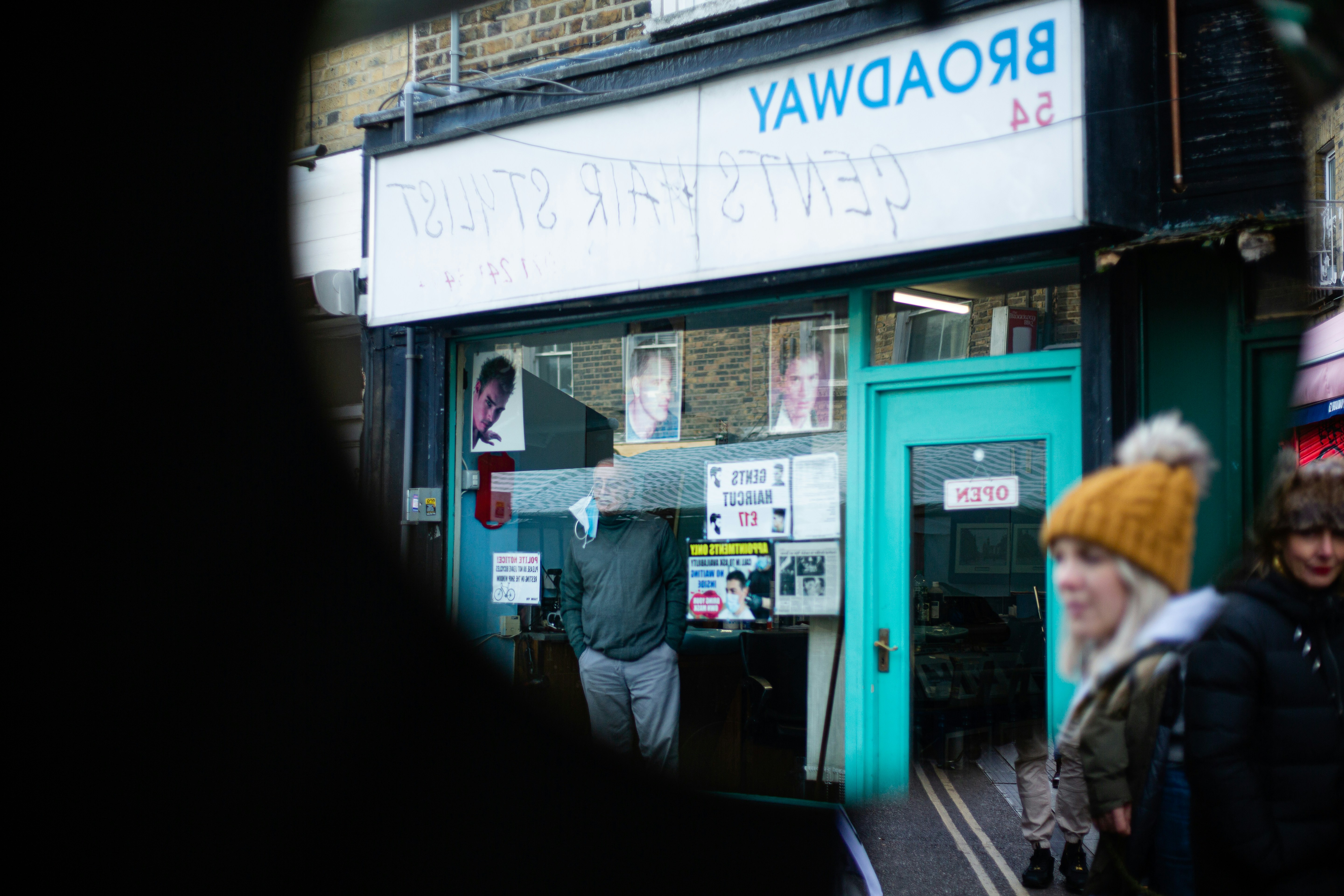 Emerald doorway amid posters and pedestrians on a busy street