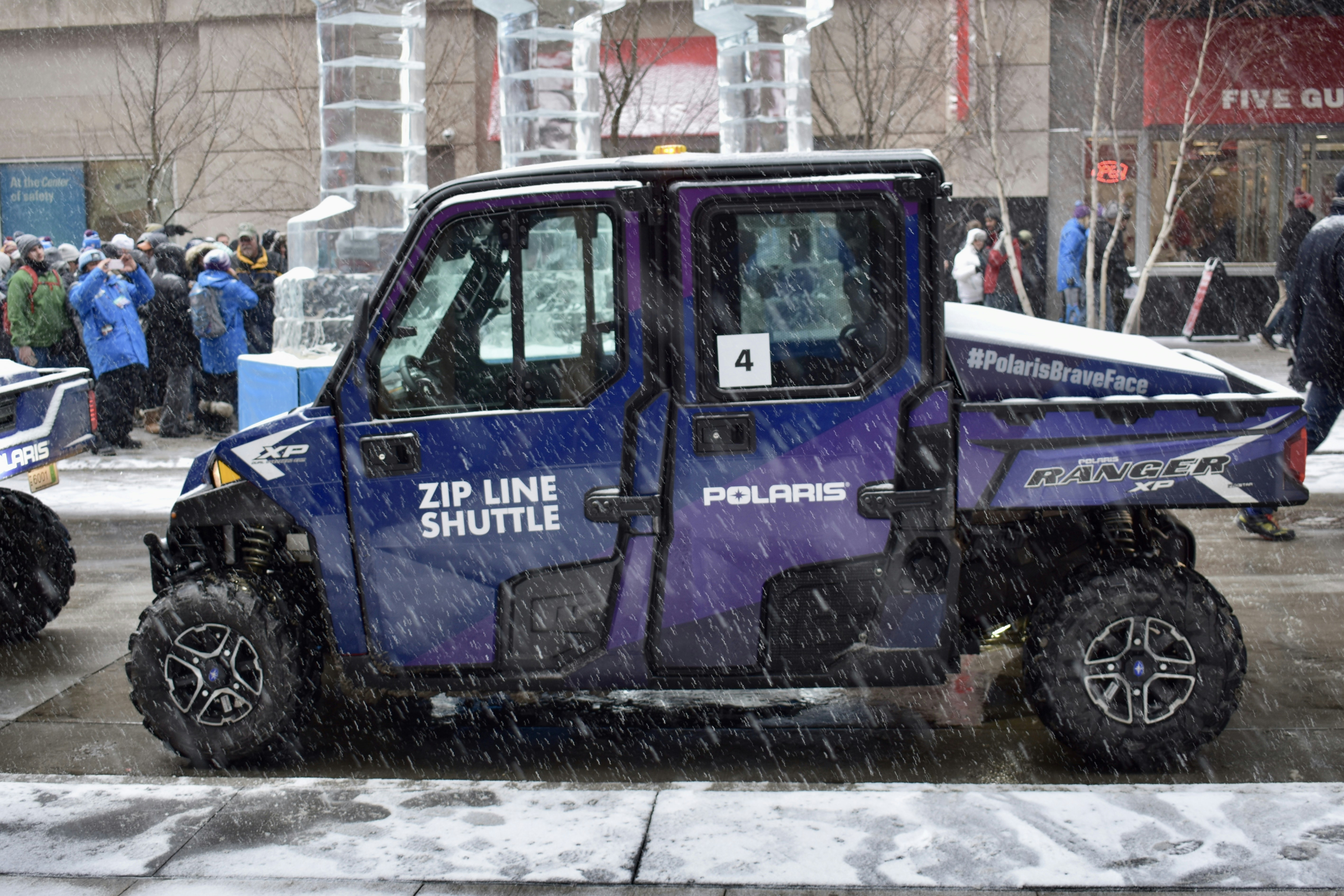 Blue Polaris Ranger Zip Line Shuttle Anchors a Snowy Street Festival