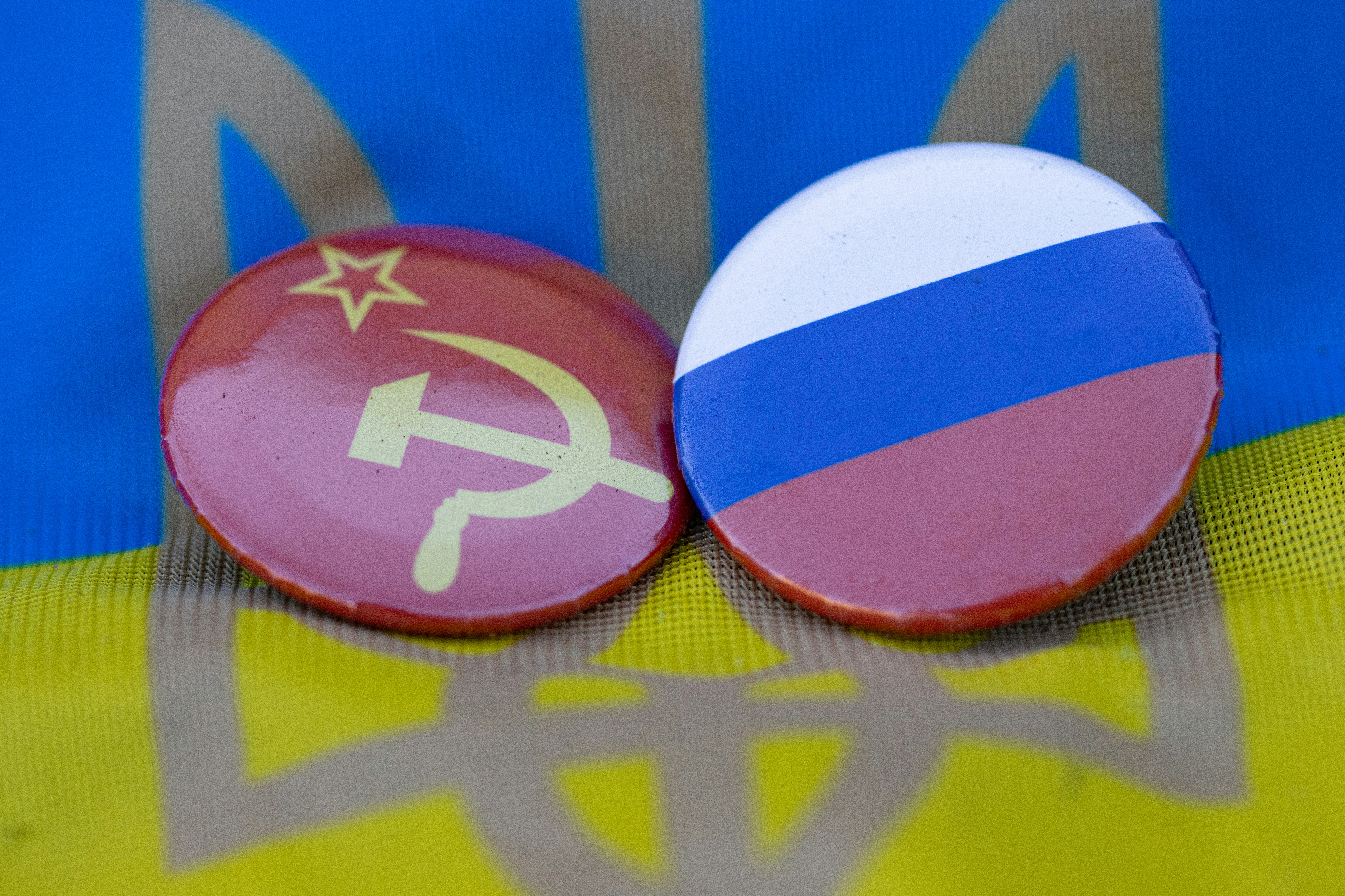 Pinned Power: Close-Up of Hammer‑and‑Sickle and Russian Flag on Sunlit Yellow Fabric