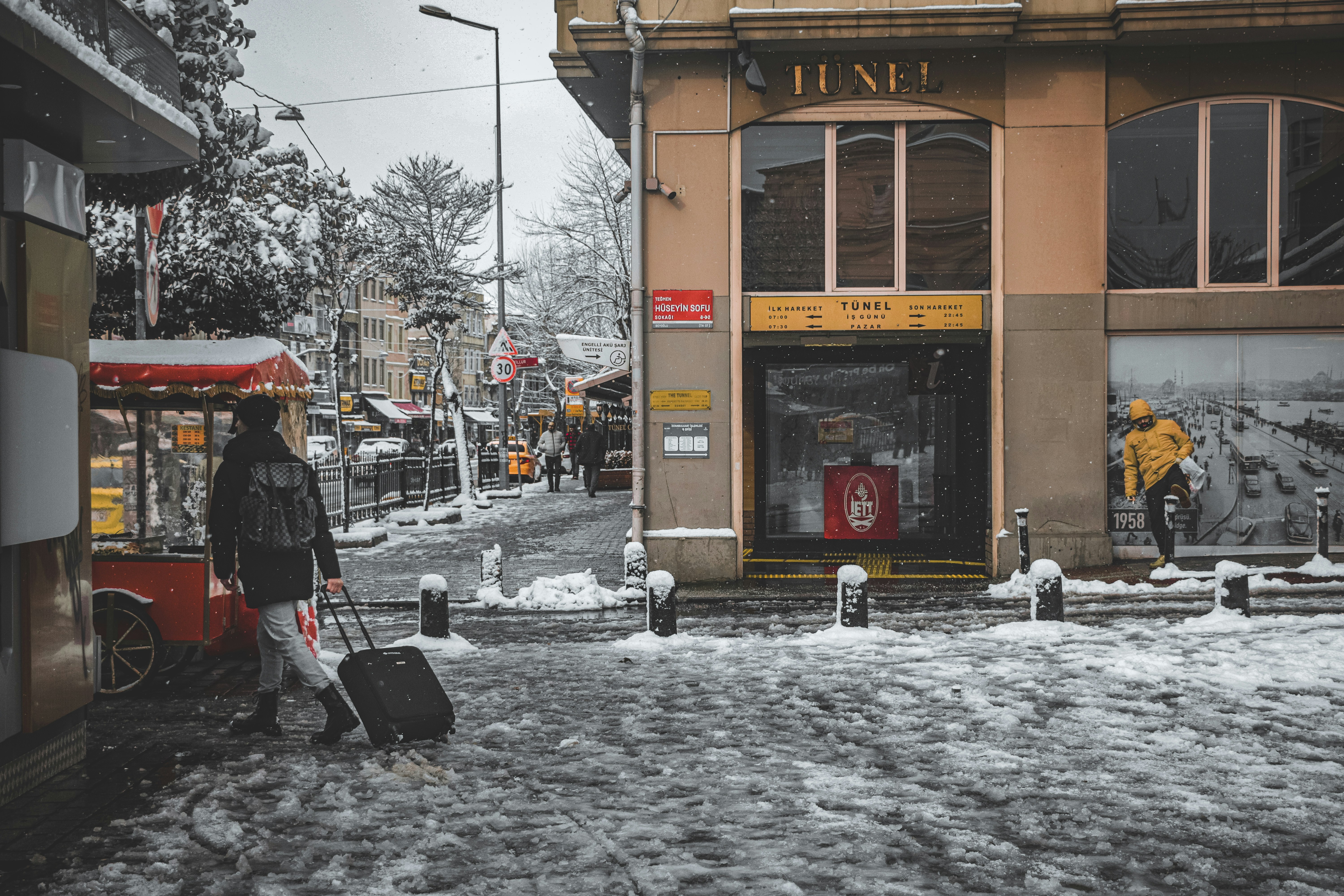 a man walking down a snow covered street holding a suitcase