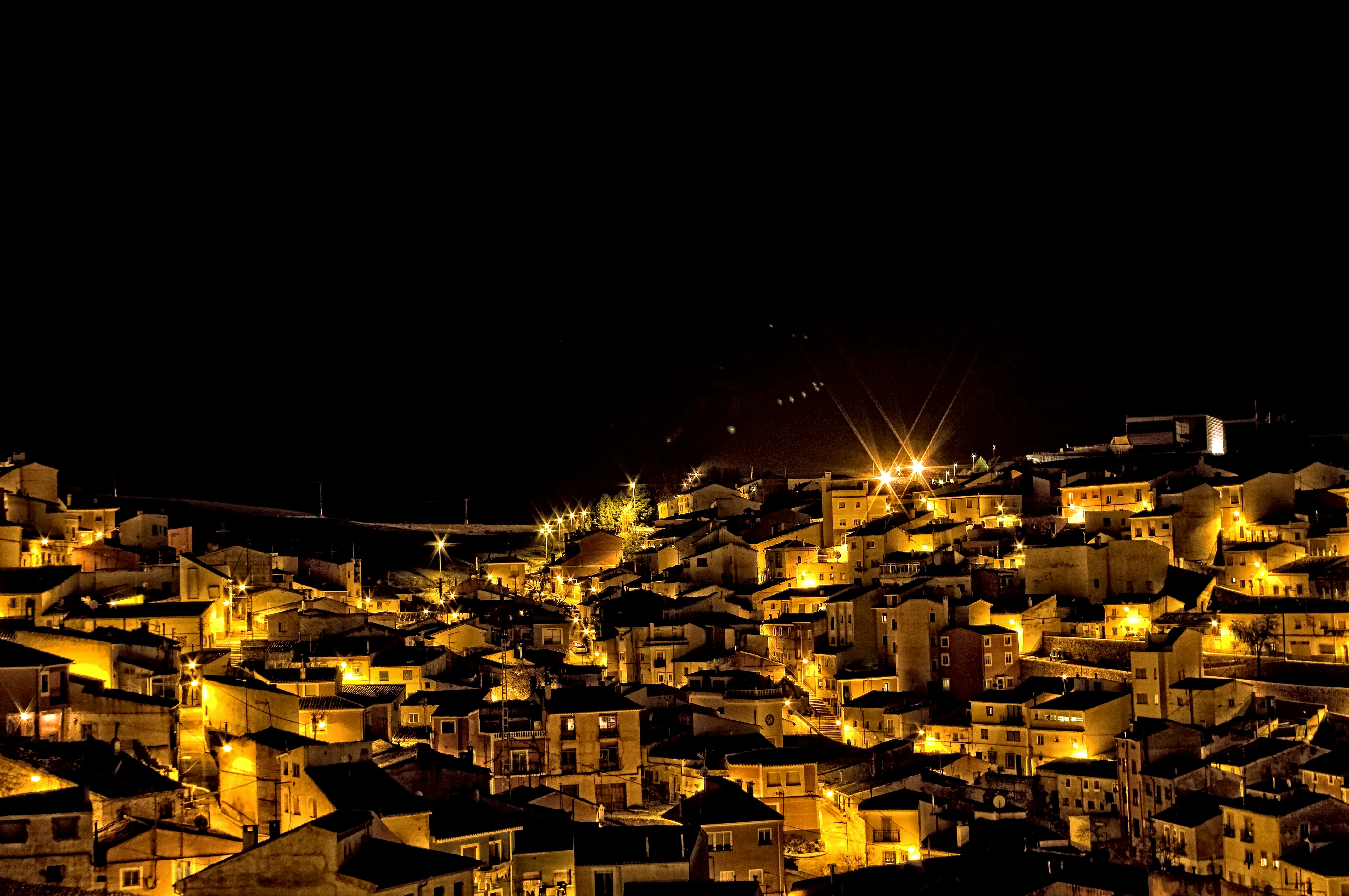 Hillside cityscape of Cuenca illuminated by warm streetlights against a dark night sky.